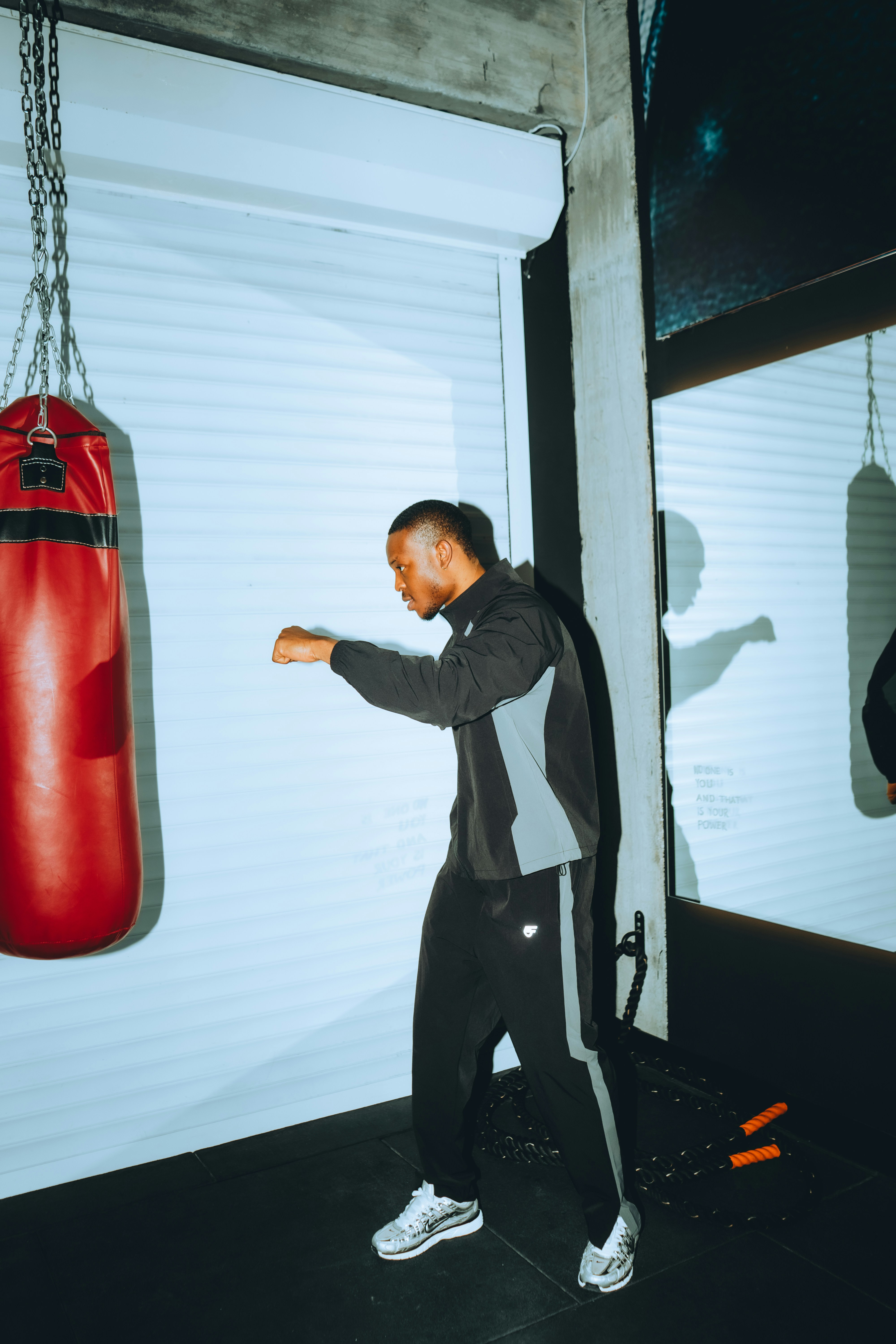 Mid-Strike in a White-Walled Gym: Solo Athlete vs. Red Heavy Bag