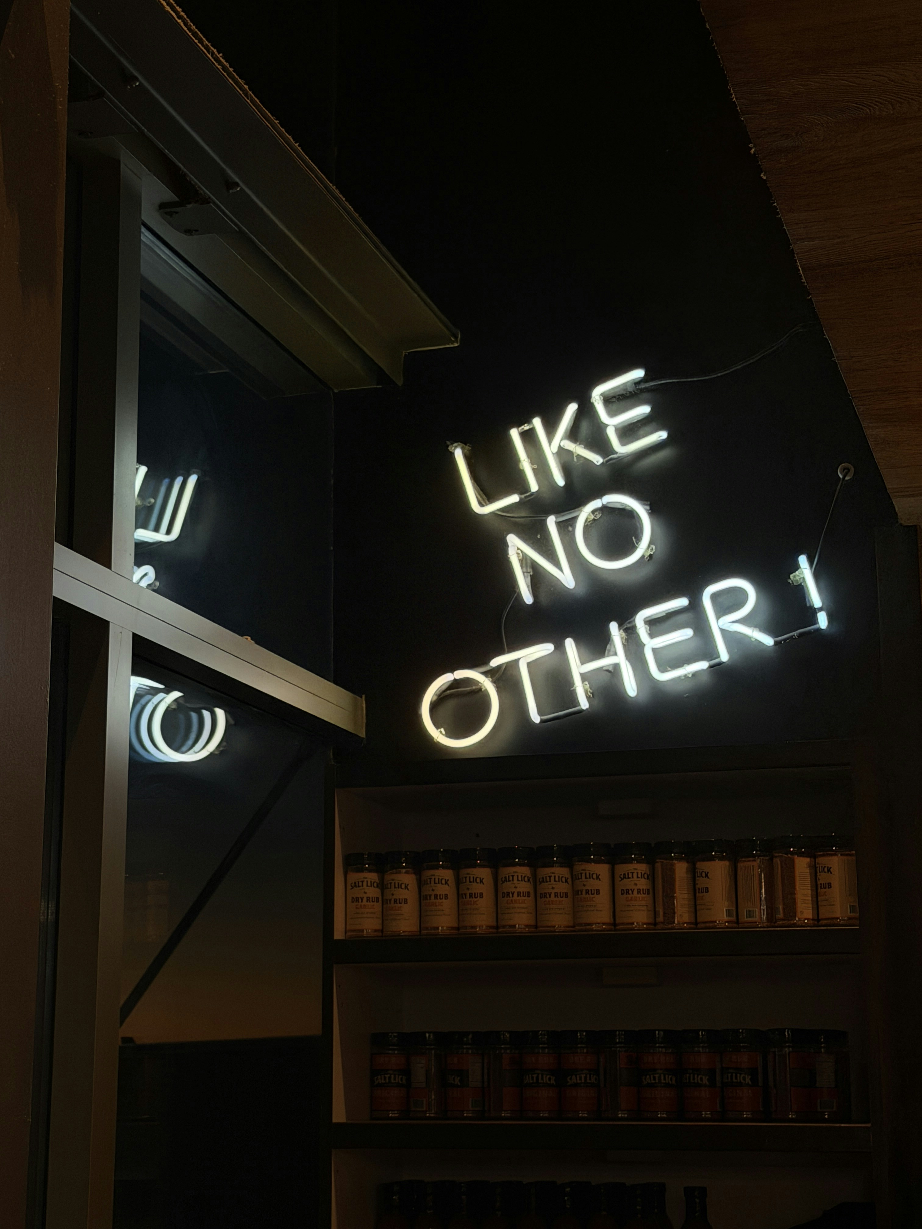 Neon Script Above Shelved Spirits: Like No Other