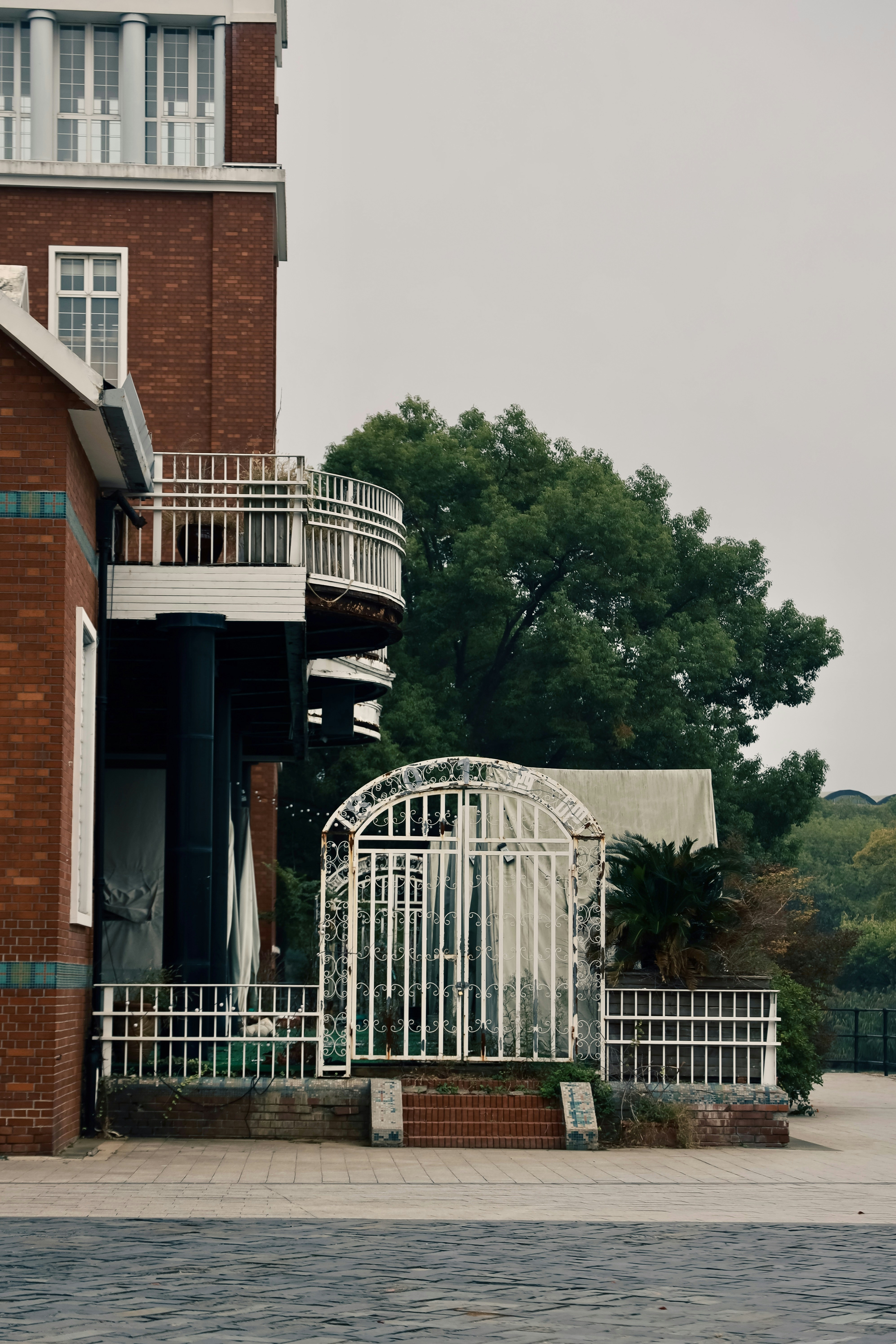 White Iron Gate Framed by Red Brick and Verdant Backdrop
