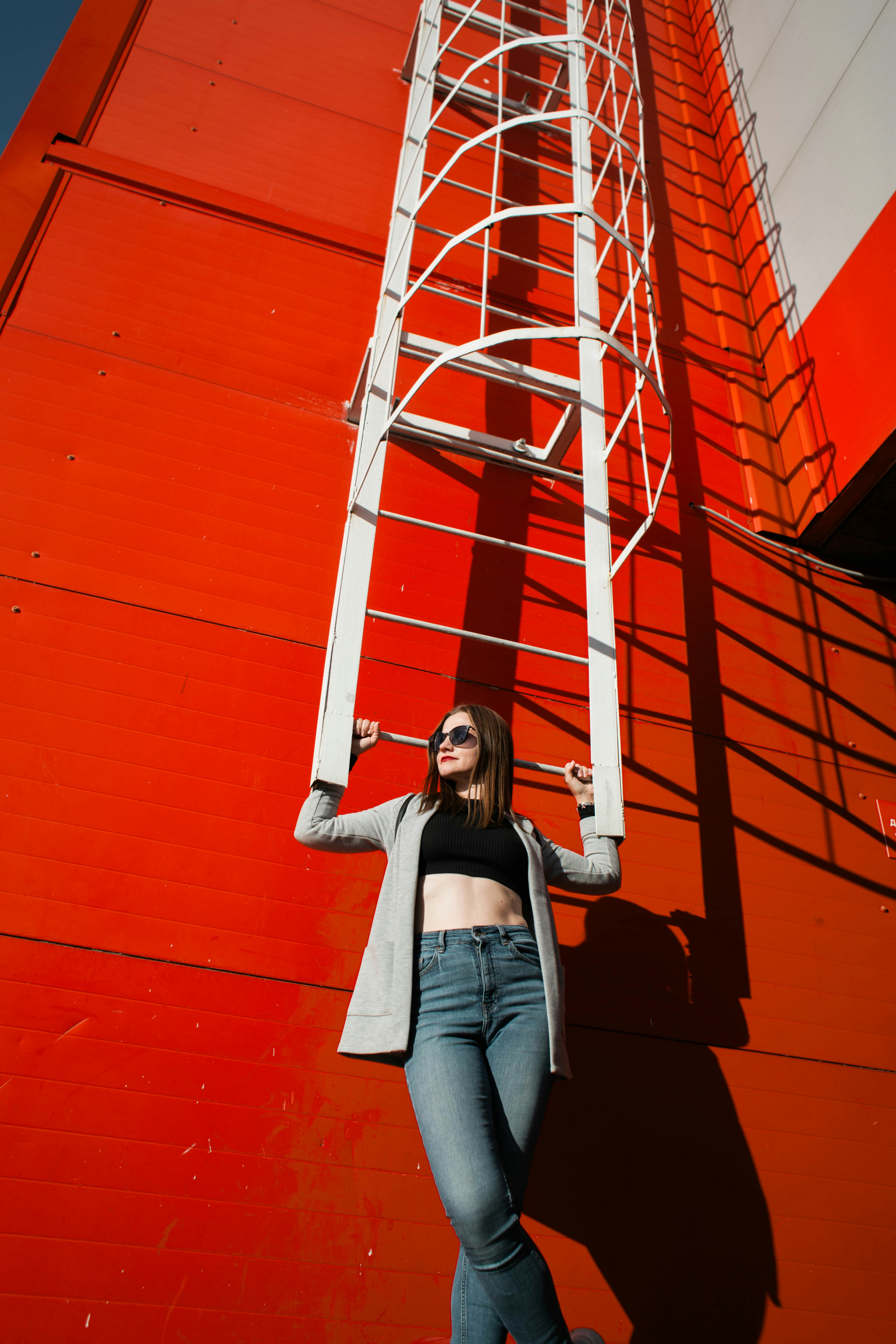 Scarlet Facade, White Ladder: A Confident Portrait by the Wall