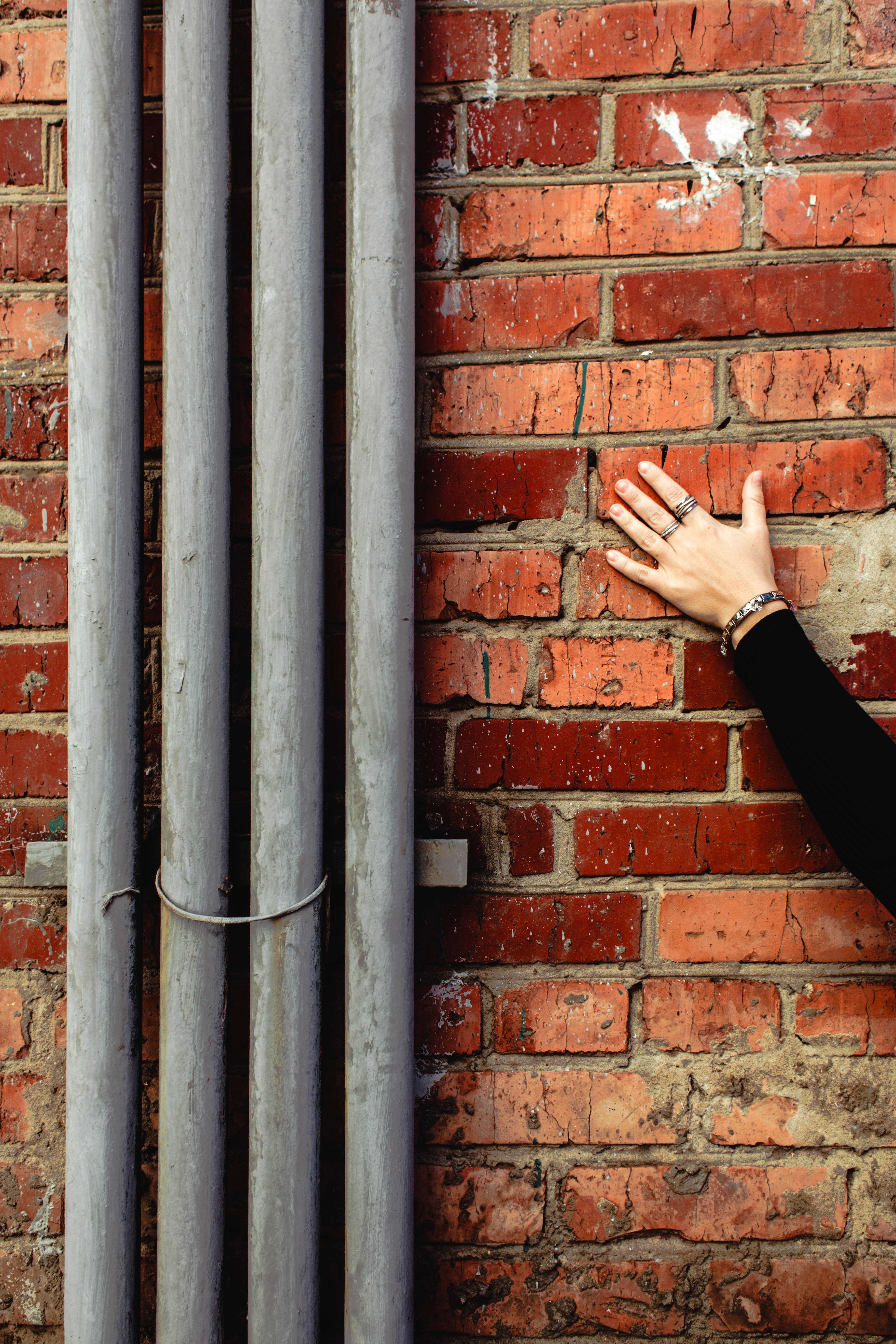 Hand on Weathered Brick: A Quiet Intersection of Flesh and Steel