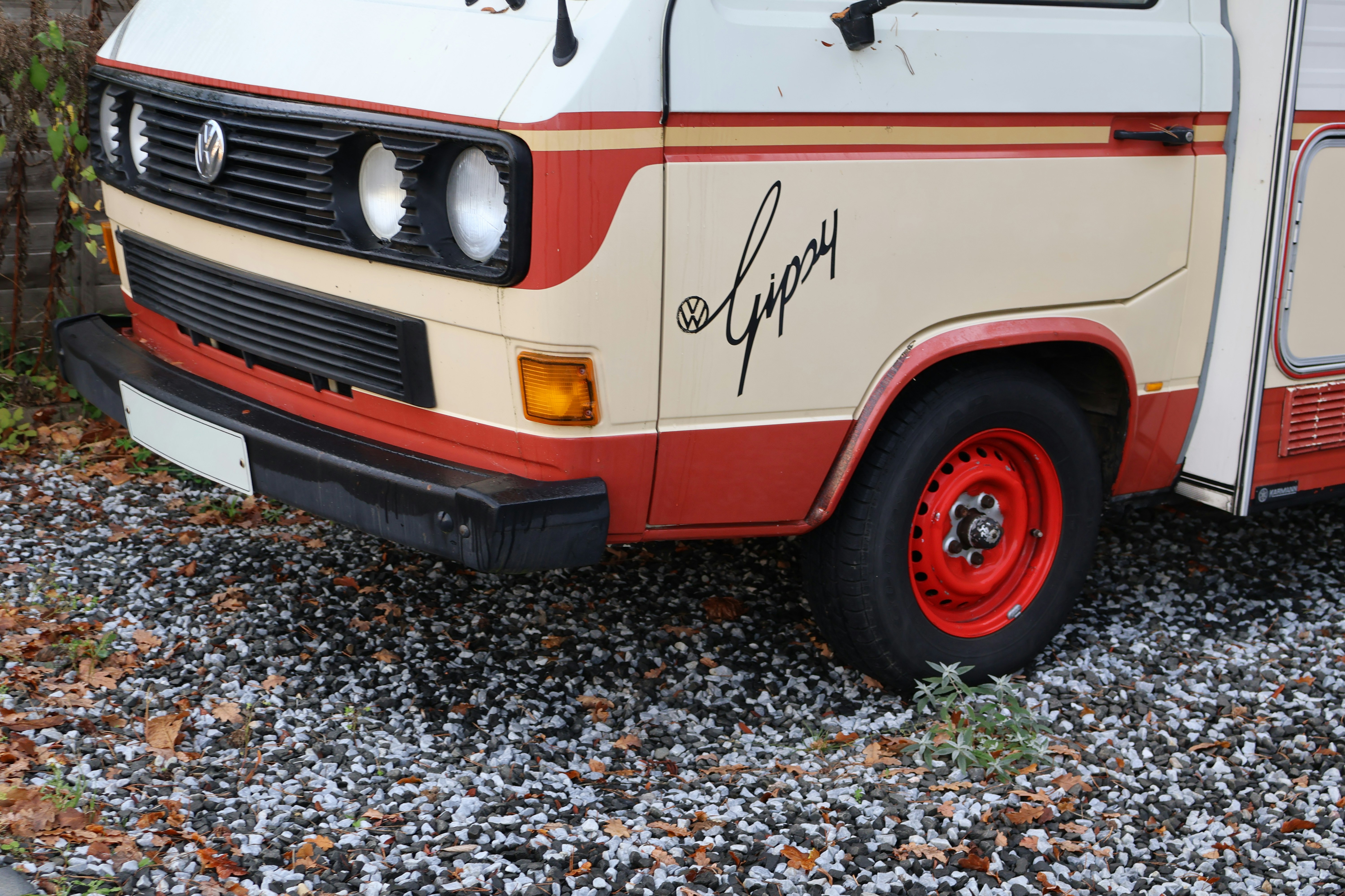 Front-Quarter View: Cream-and-Red Vintage Camper on a Pebble Bed