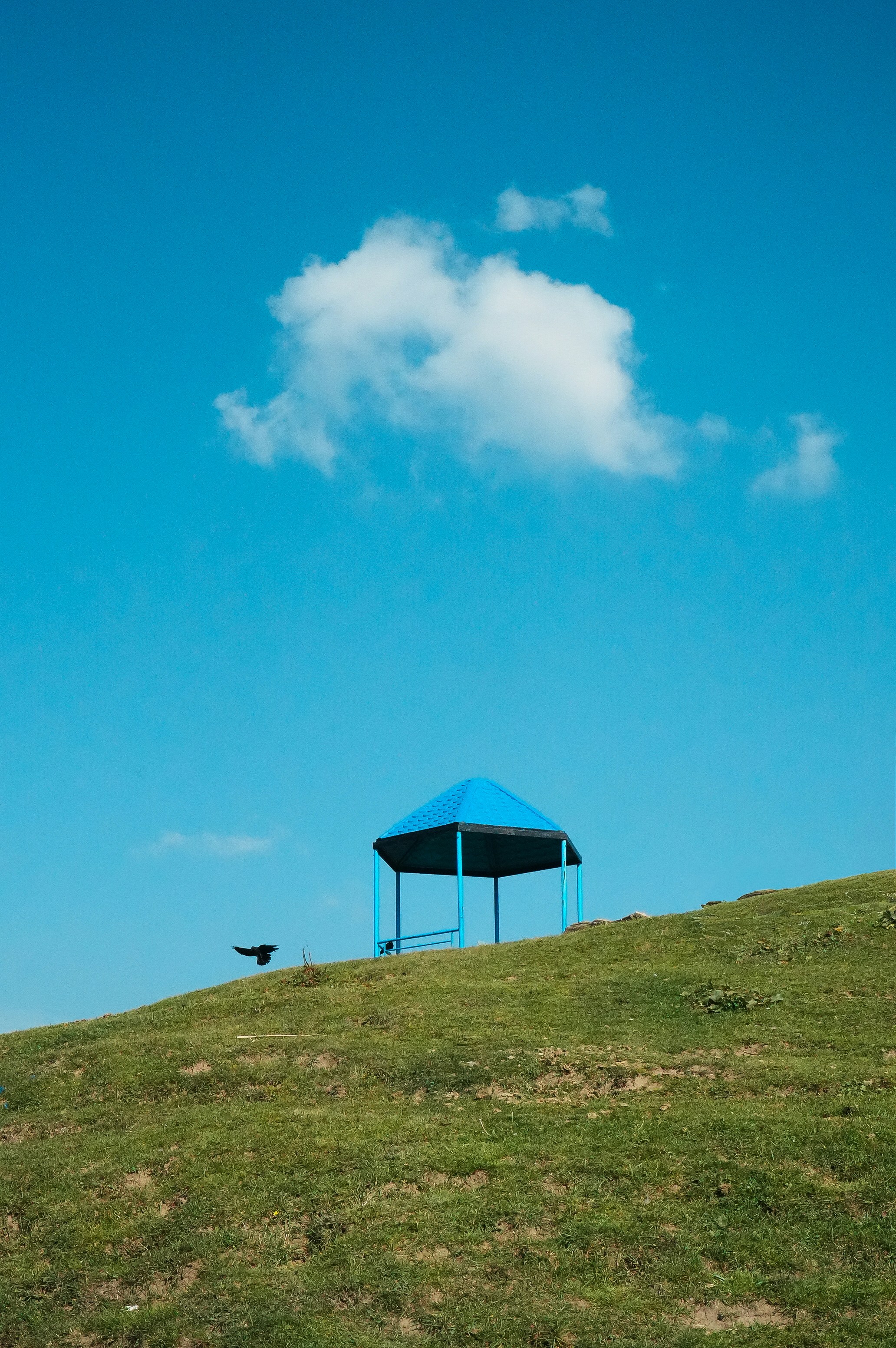 Blue Pavilion on a Gentle Hill Under a Boundless Sky