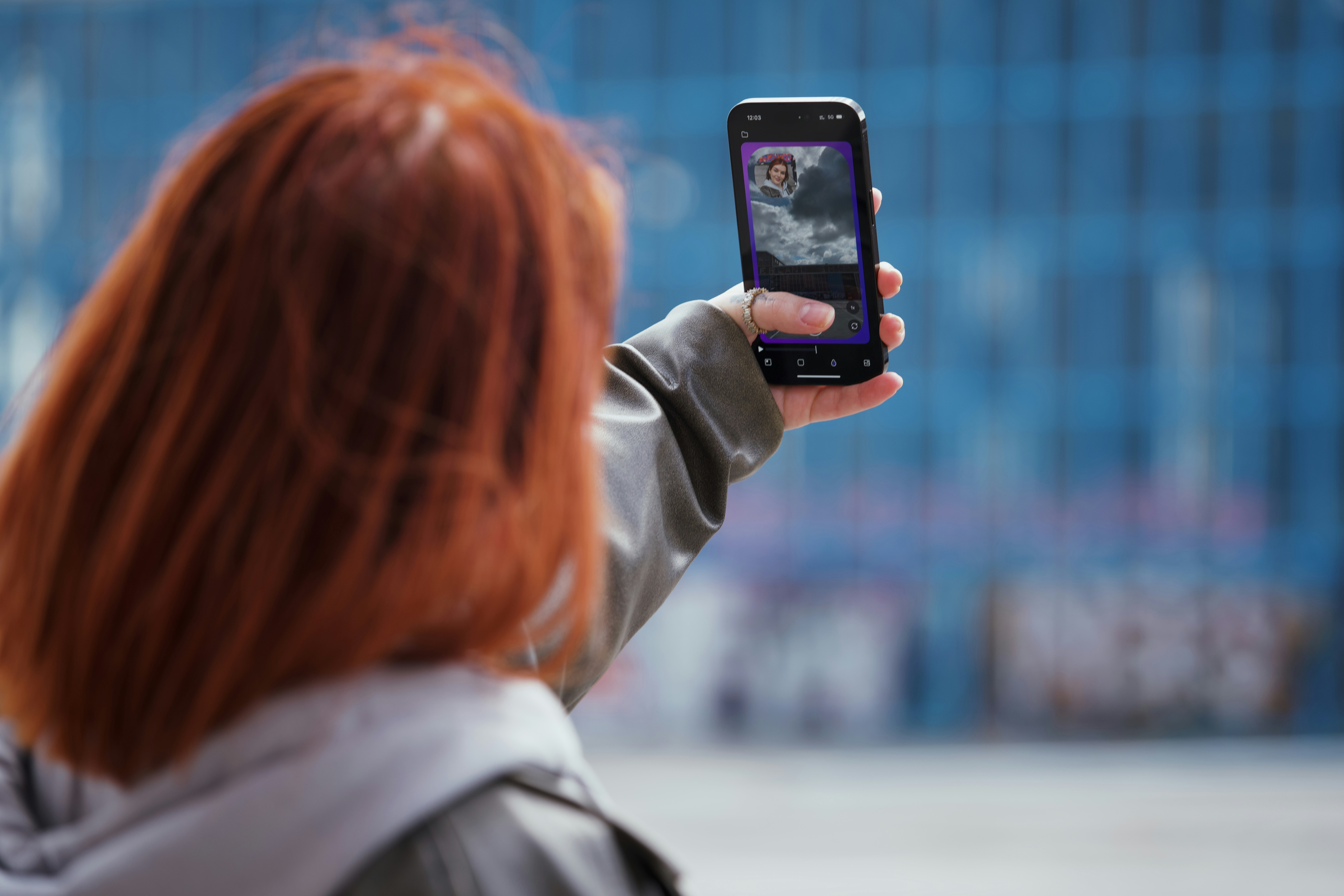 Azure Glass Selfie: A Handheld Moment in Front of a Blue Facade