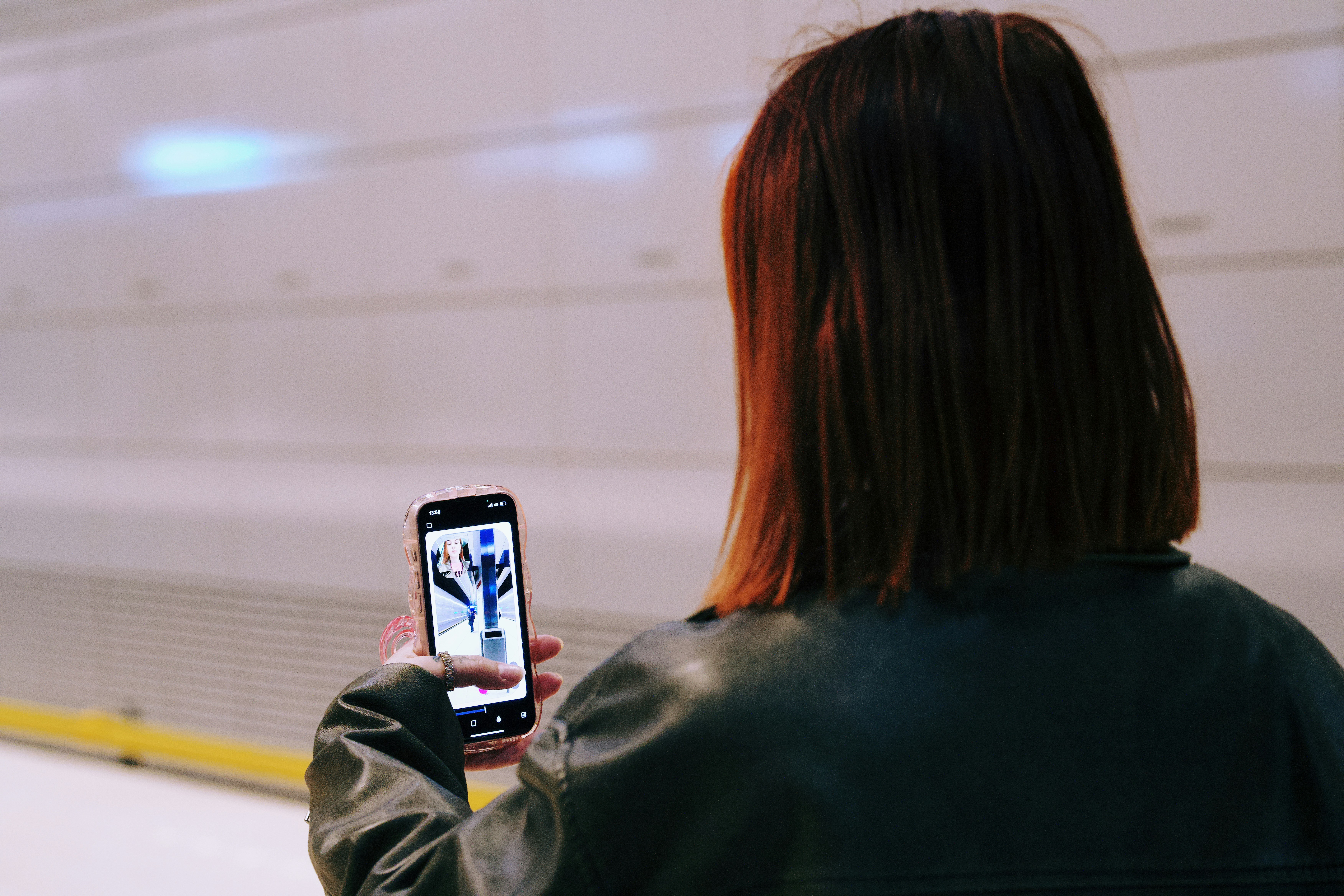 Phone-Screen Portrait in a Neon-Washed Transit Corridor