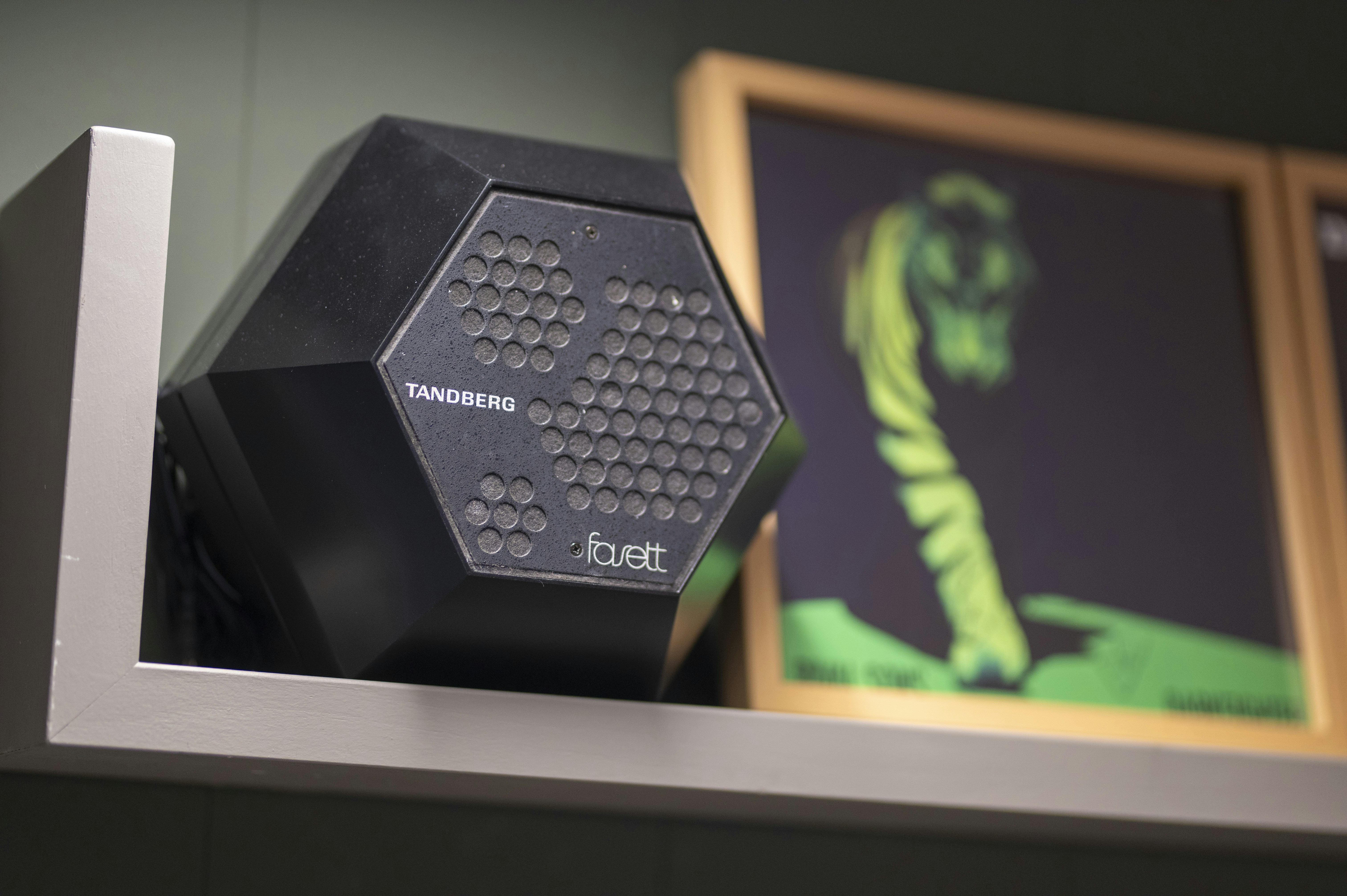 Hexagonal Tandberg on a shelf beneath a neon-green portrait