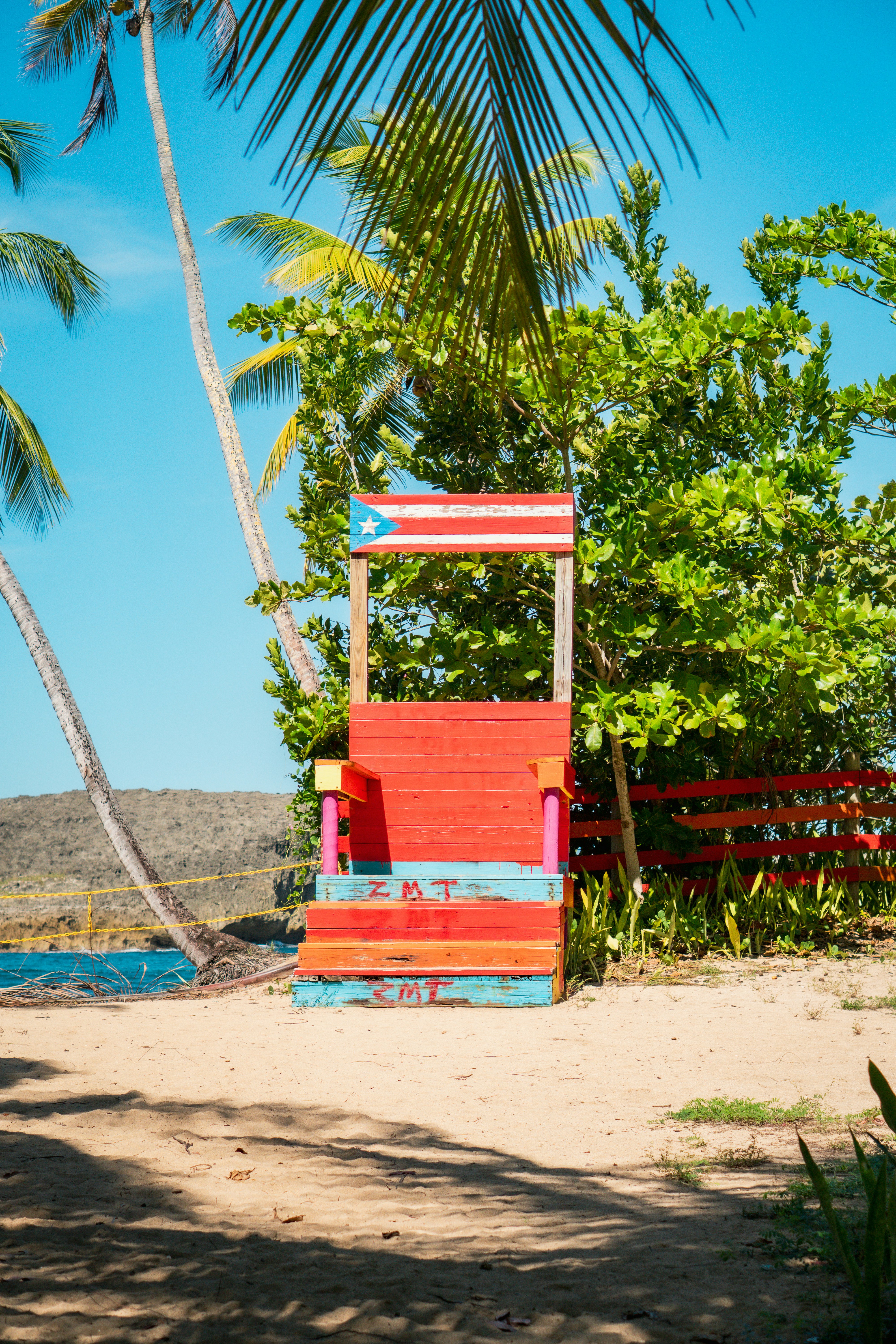 Sunlit Lifeguard Chair Framed by Palm Fronds on a Caribbean Beach