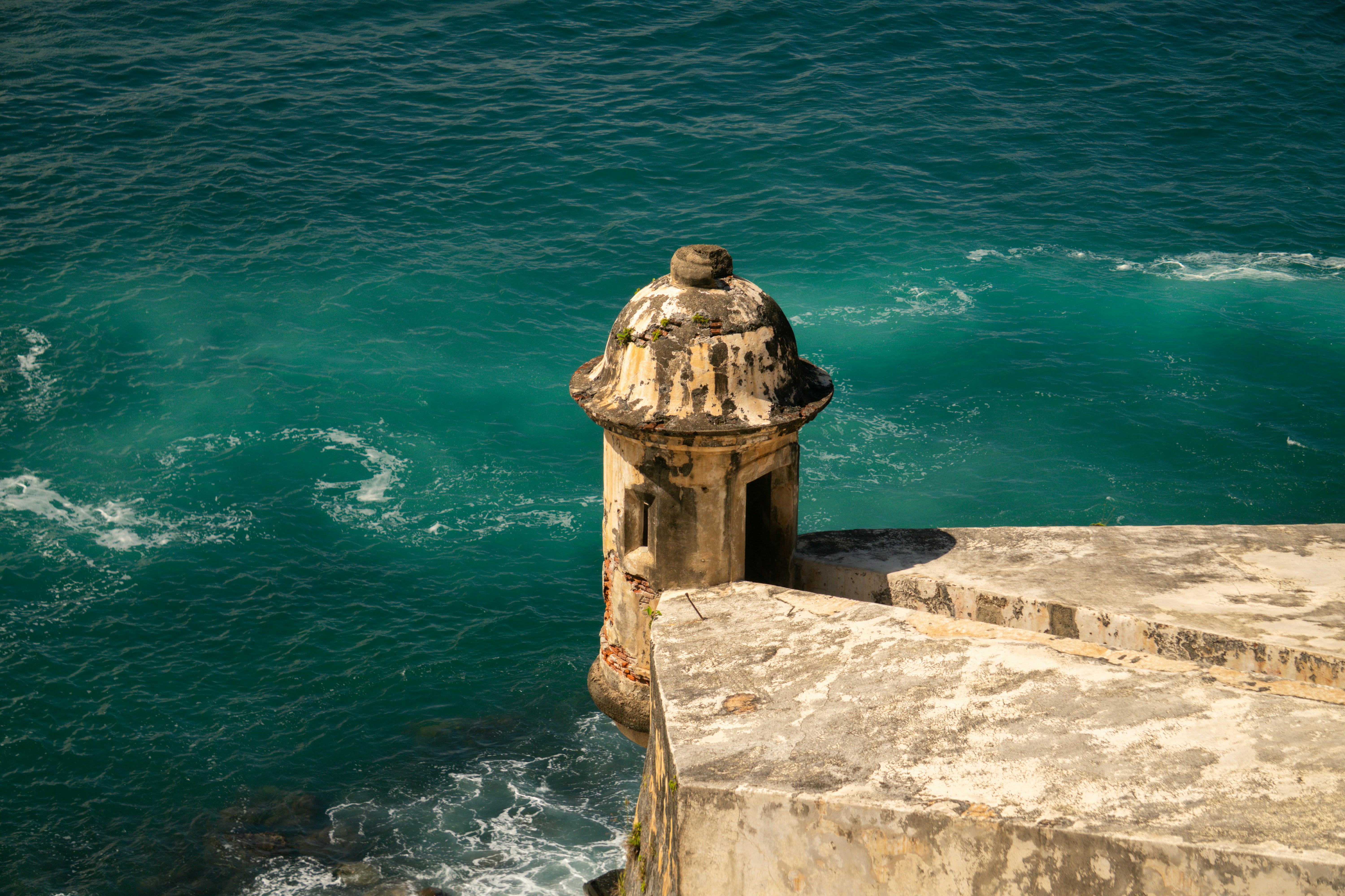 Old stone turret overlooks turquoise ocean waves photo – Free ...
