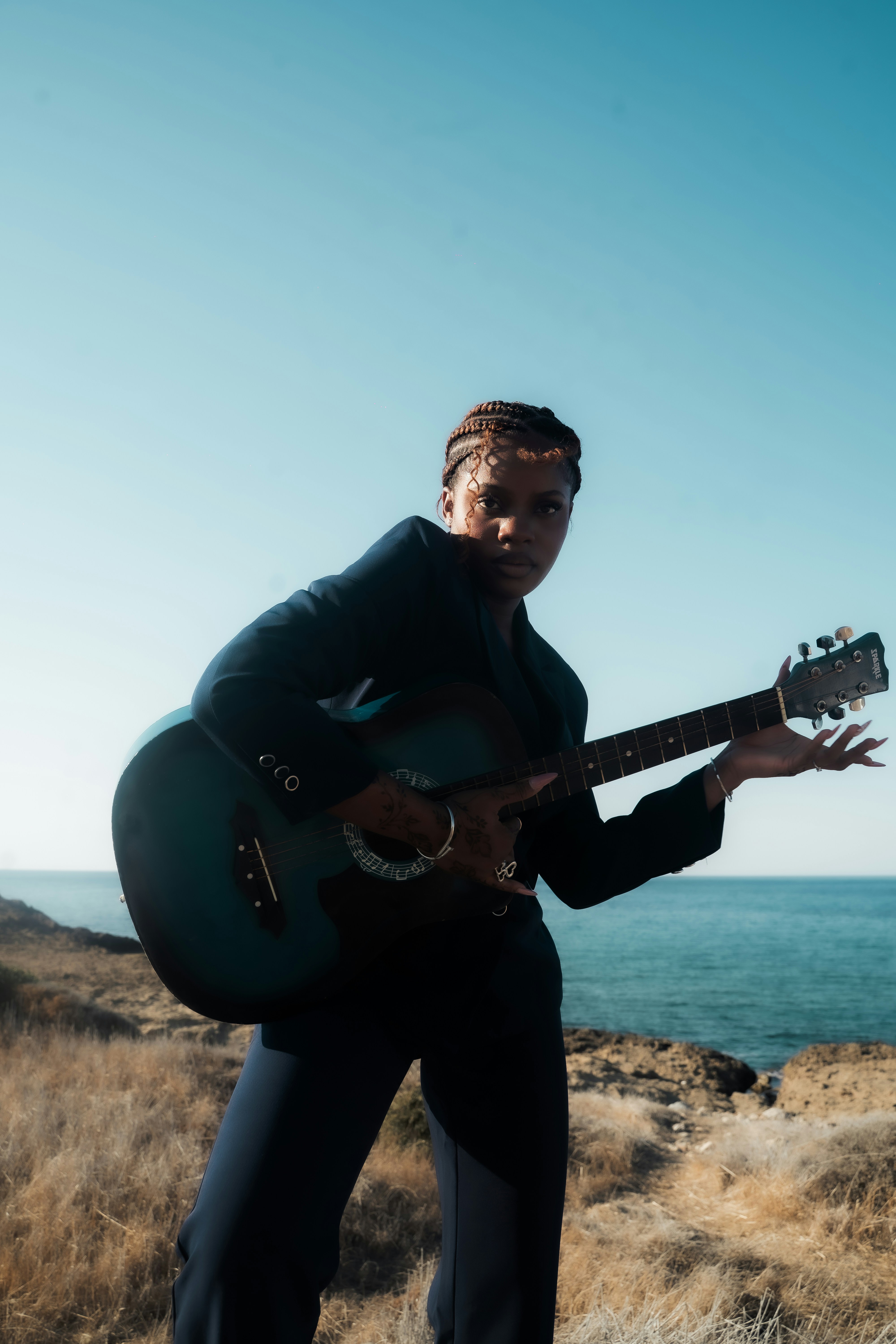 Clifftop Serenade: A Guitarist Cast in Sea-Breeze Light
