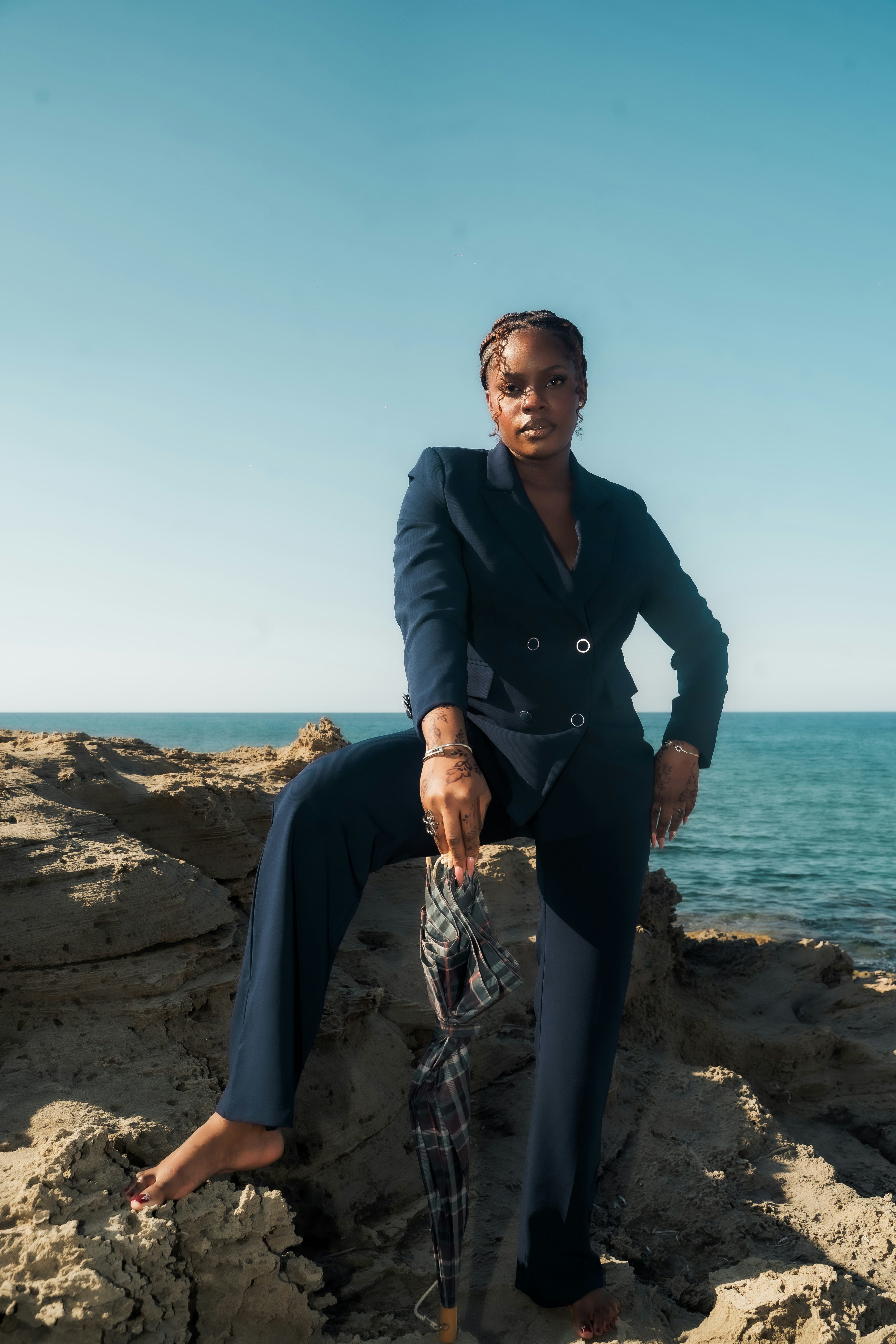 Coastal Command: A Bold Navy Suit Stands Ground on Weathered Rocks