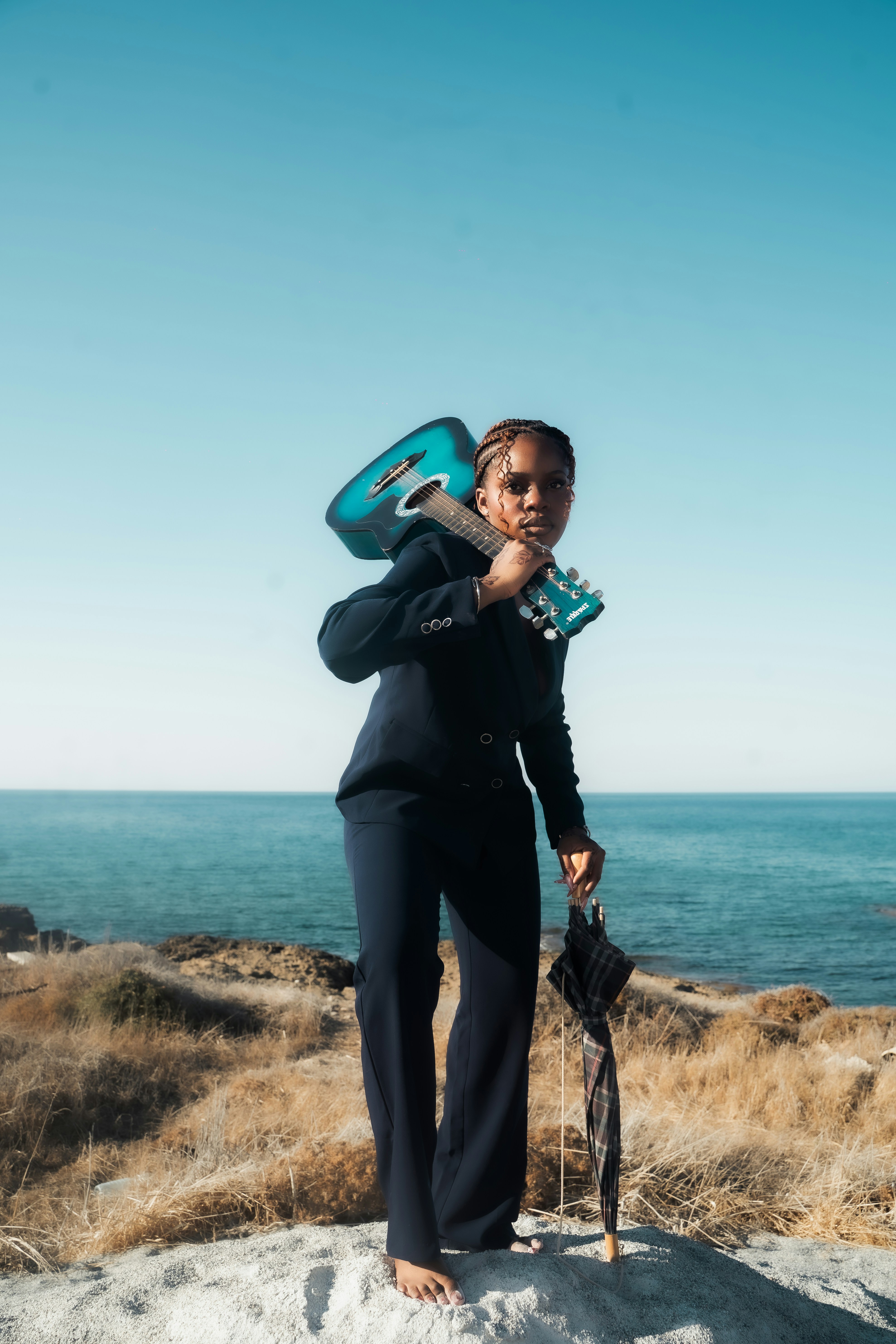 Coastal Serenade: Barefoot Suit Clad Player with a Teal Guitar
