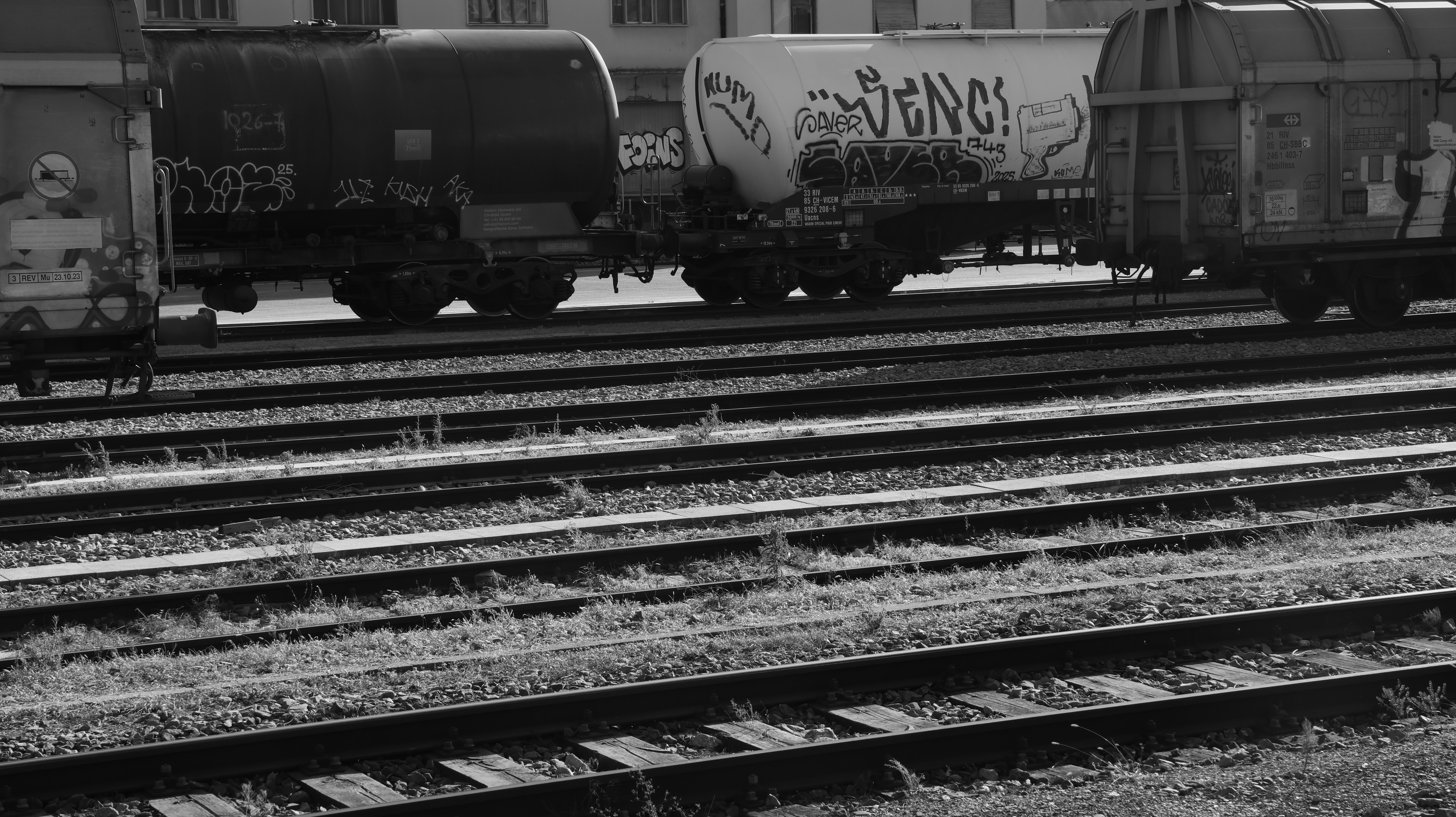 Graffiti on a Silent Freight Tanker in a Monochrome Rail Yard