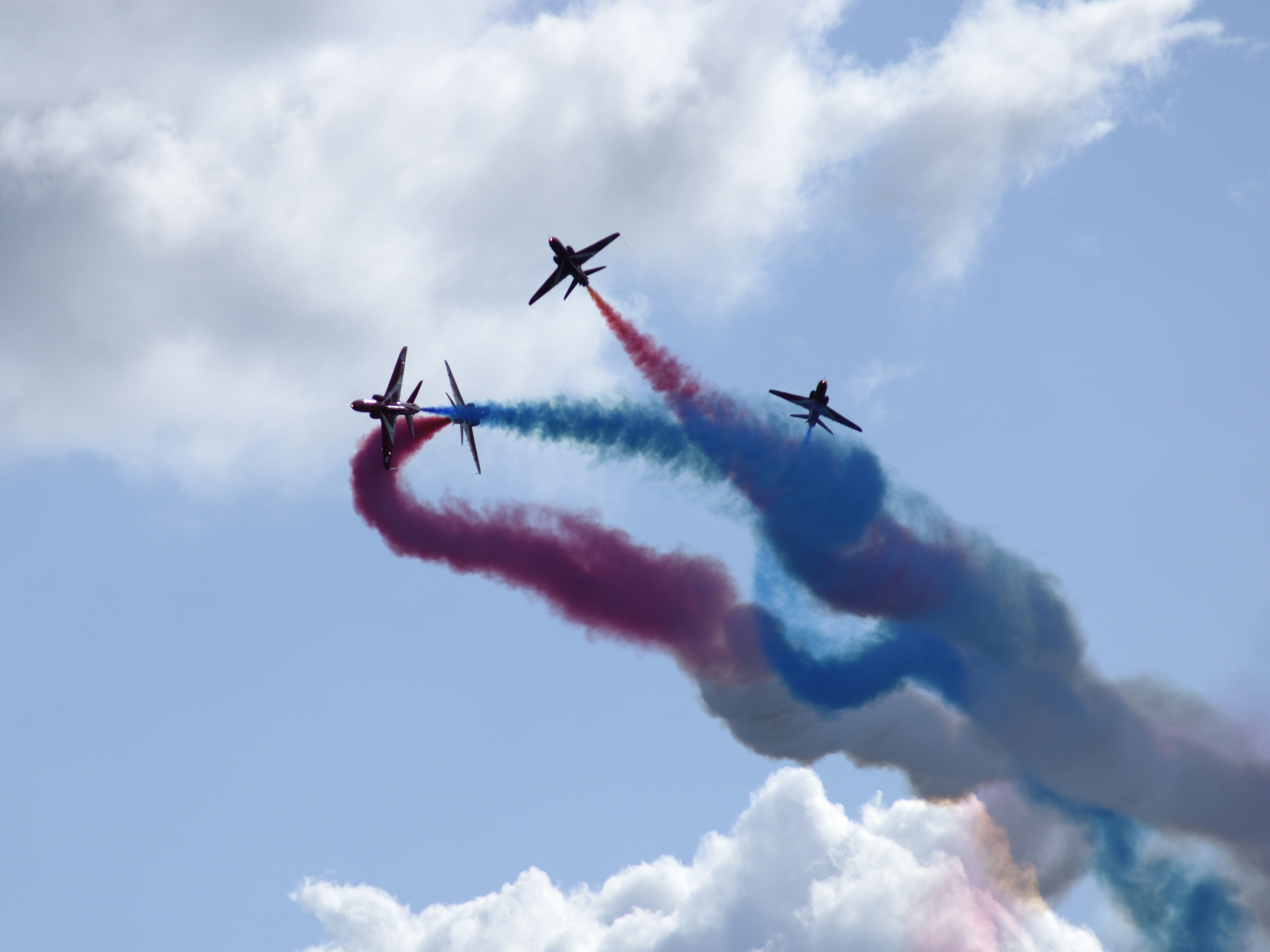 Crimson and Cobalt Smoke Triad Over a Sky of Clouds