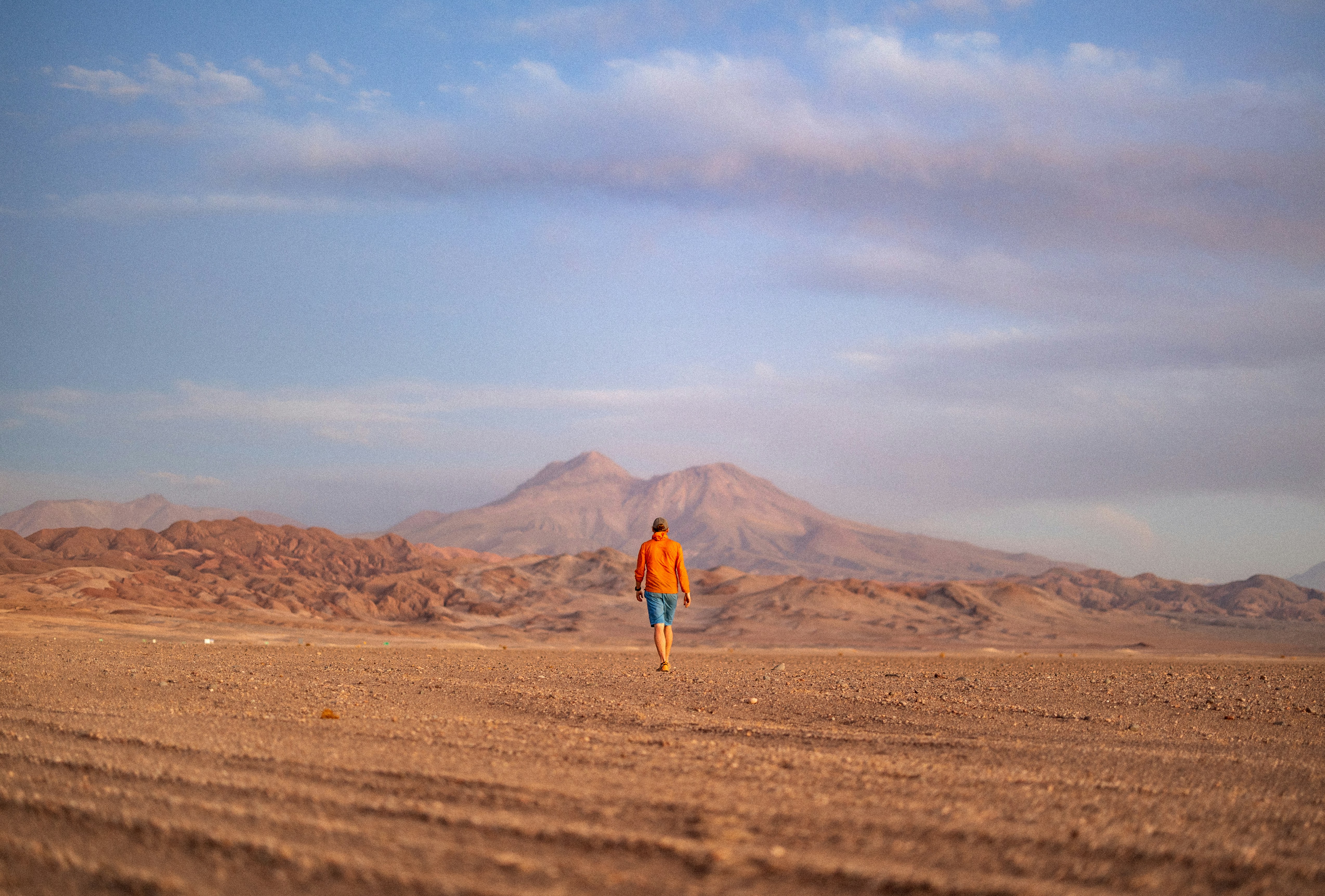 Lone Traveler on a Desert Plain Toward a Rugged Mountain Horizon