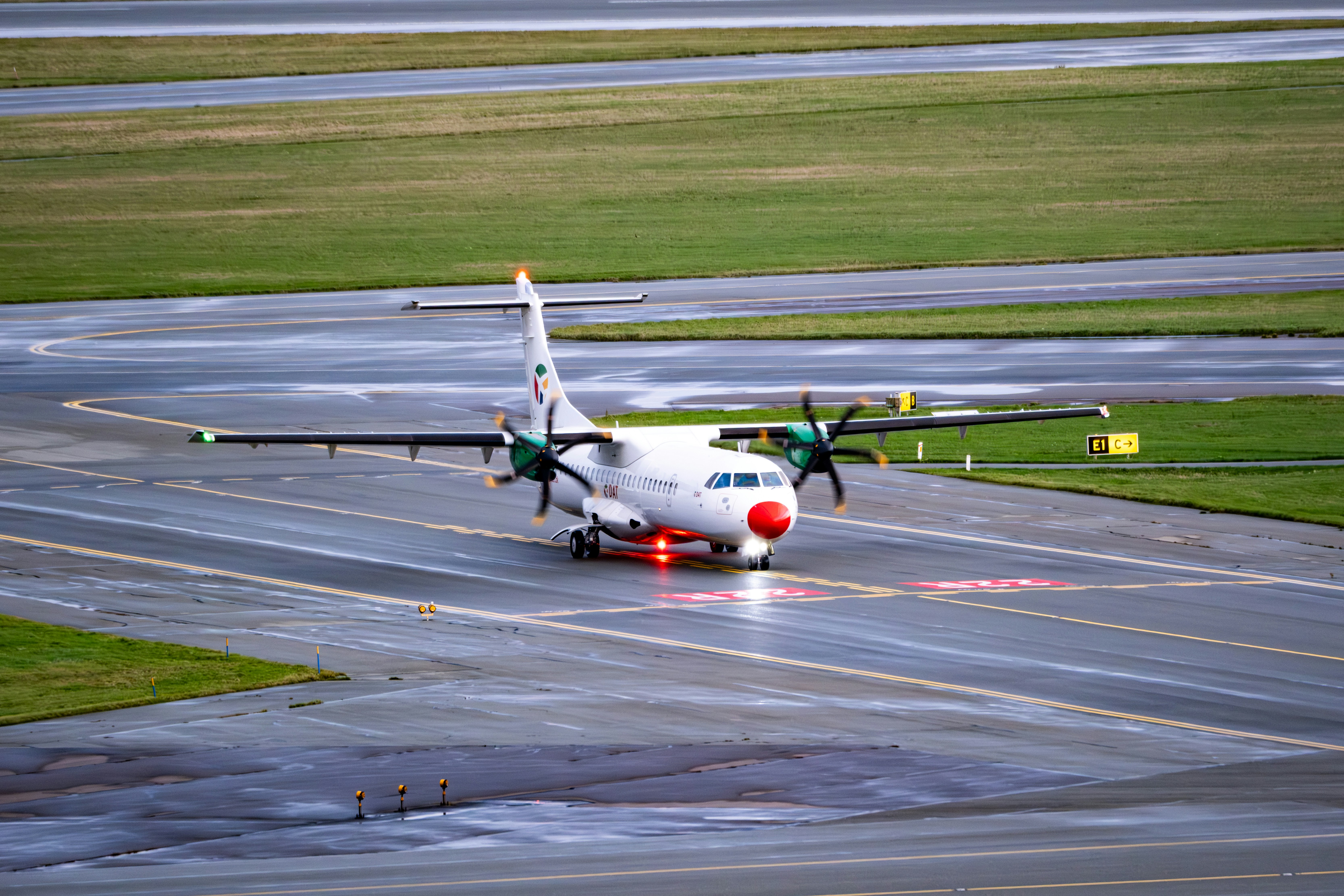 Red-nosed turboprop on a rain-slick runway, a quiet moment at a regional airport