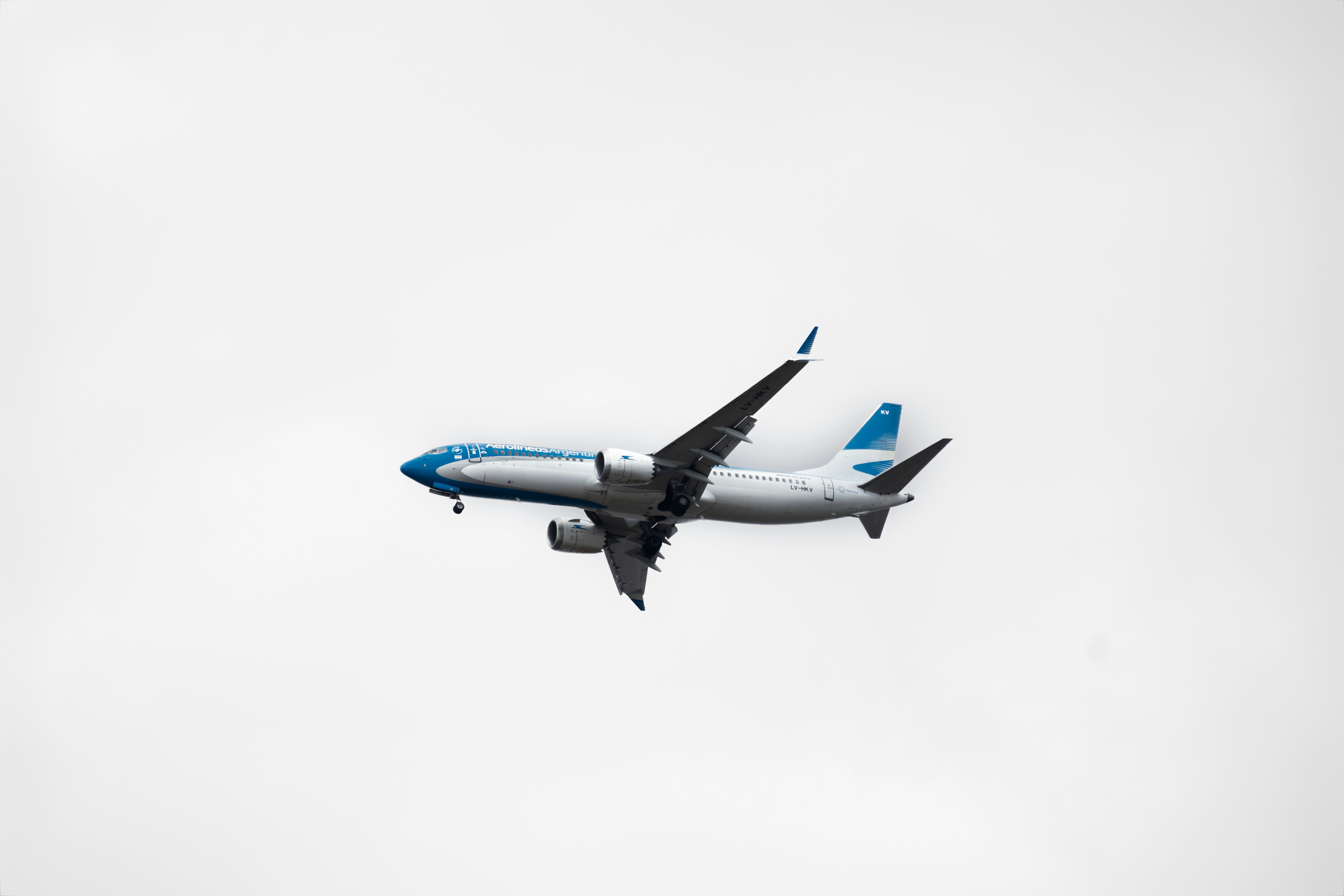 Azure-tailed airliner gliding through a pale, uncluttered sky