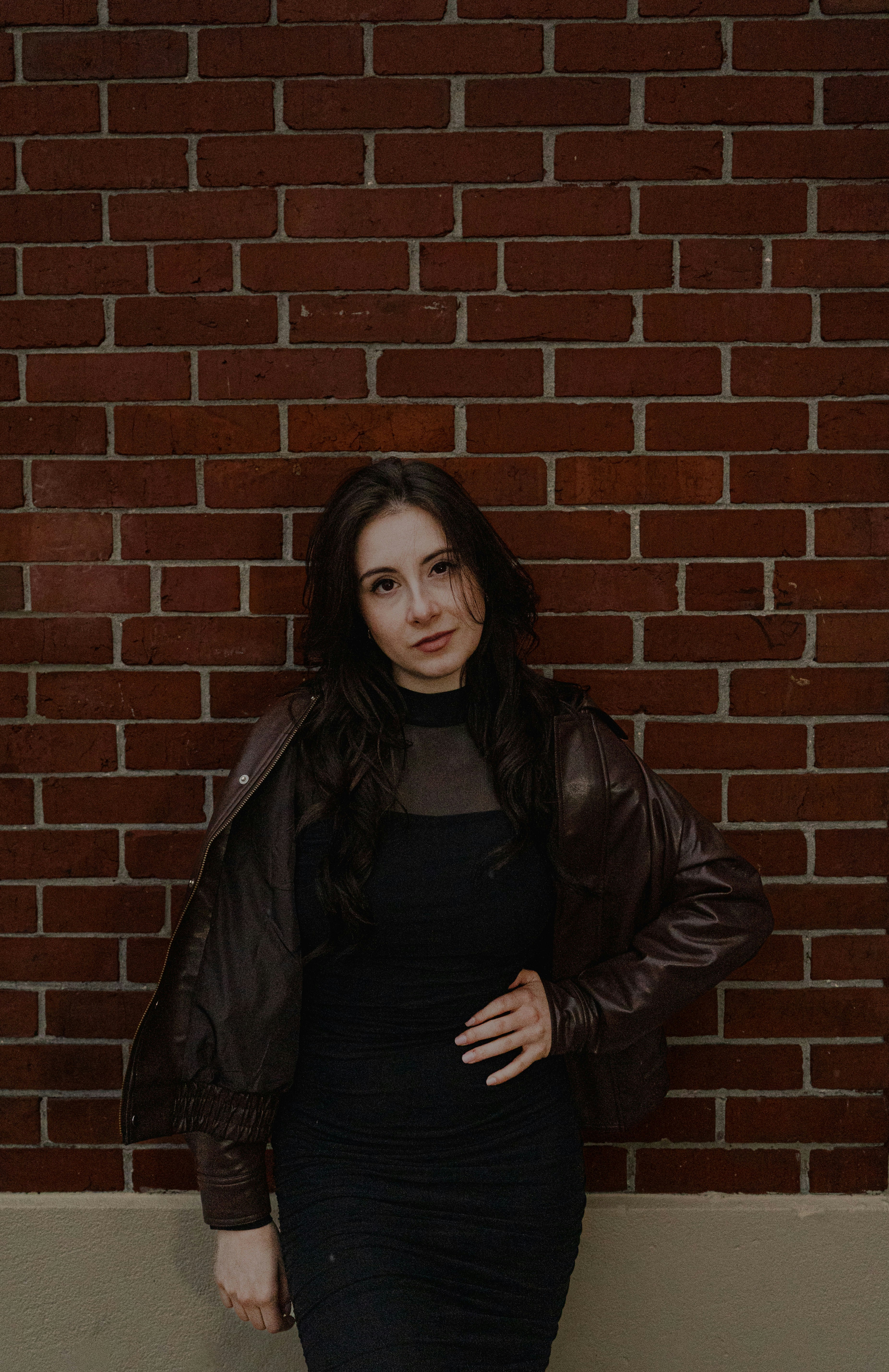 Female model standing against a brick wall