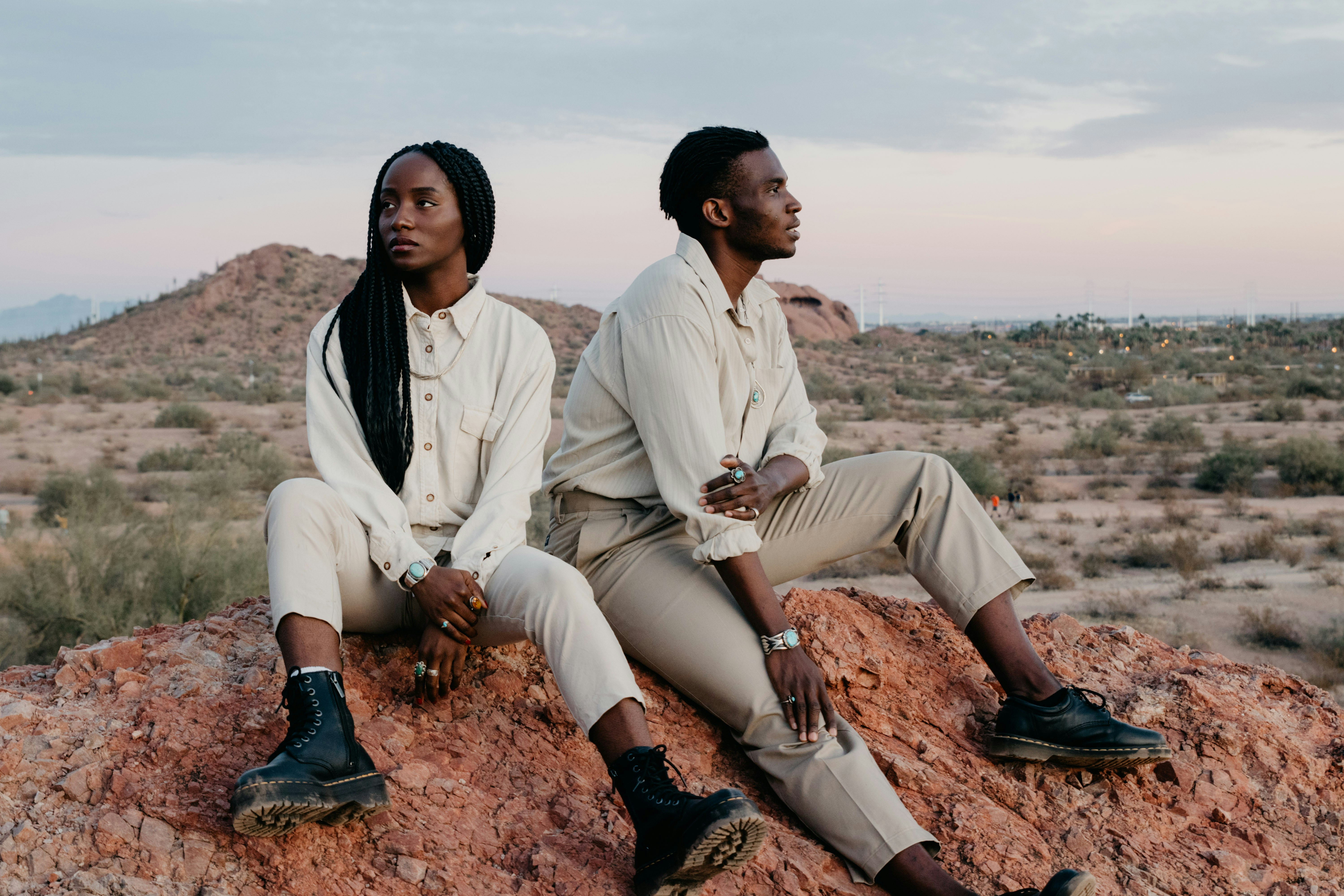 Quiet Resolve on a Desert Ridge: Linen-clad Duo Paused in Red Rock