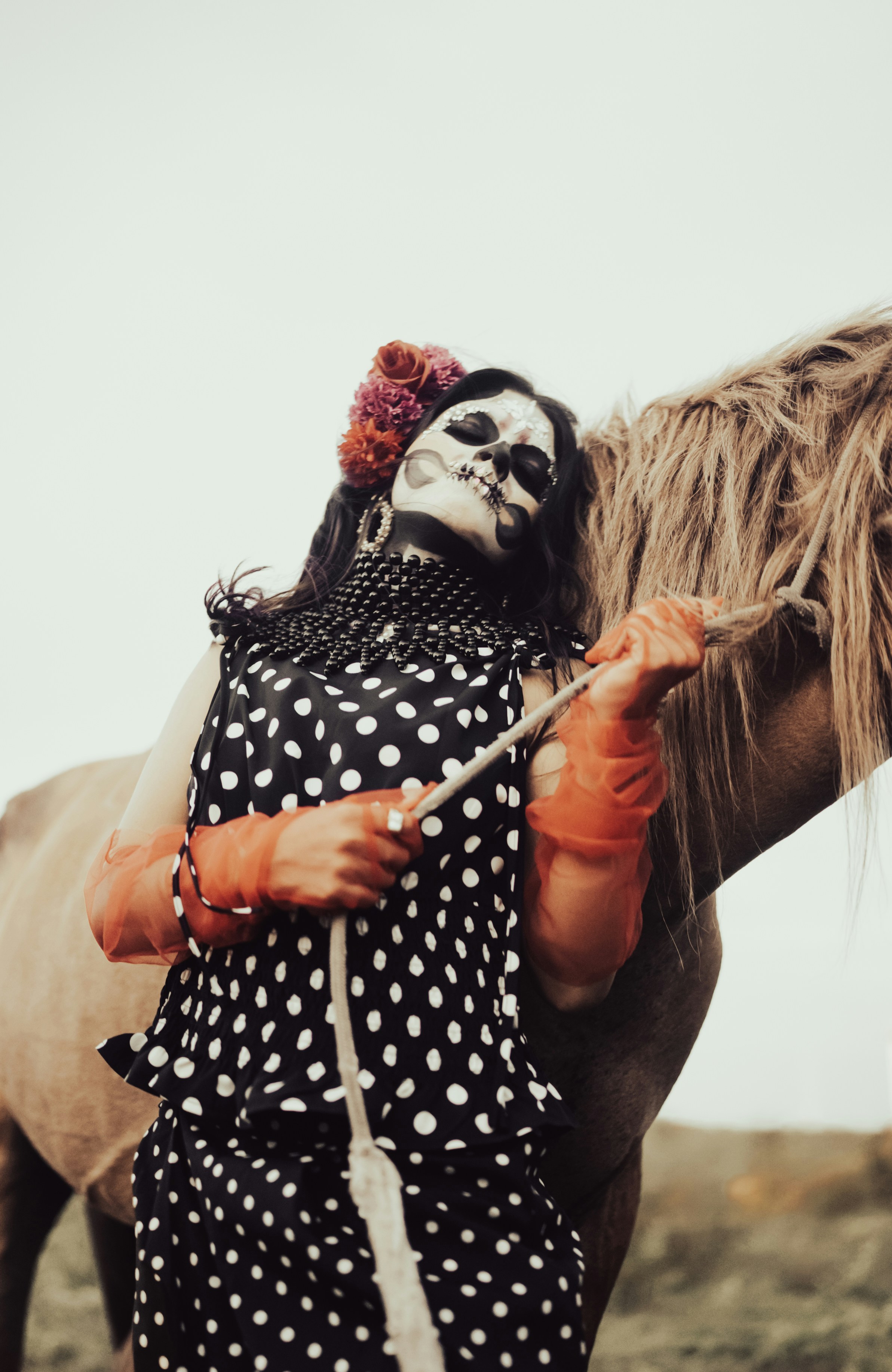Sugar Skull Rider in a Polka-Dot Dress Guides a Horse Across an Open Field
