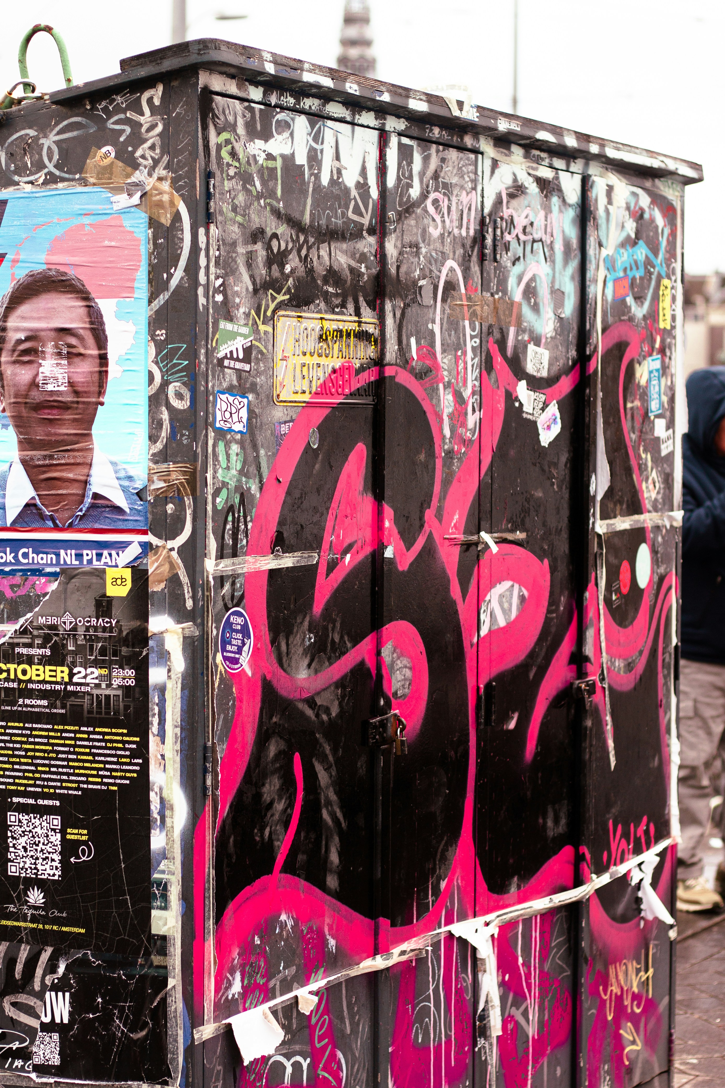 Crimson Whorls Flow Across a Graffiti-Scrawled Utility Cabinet
