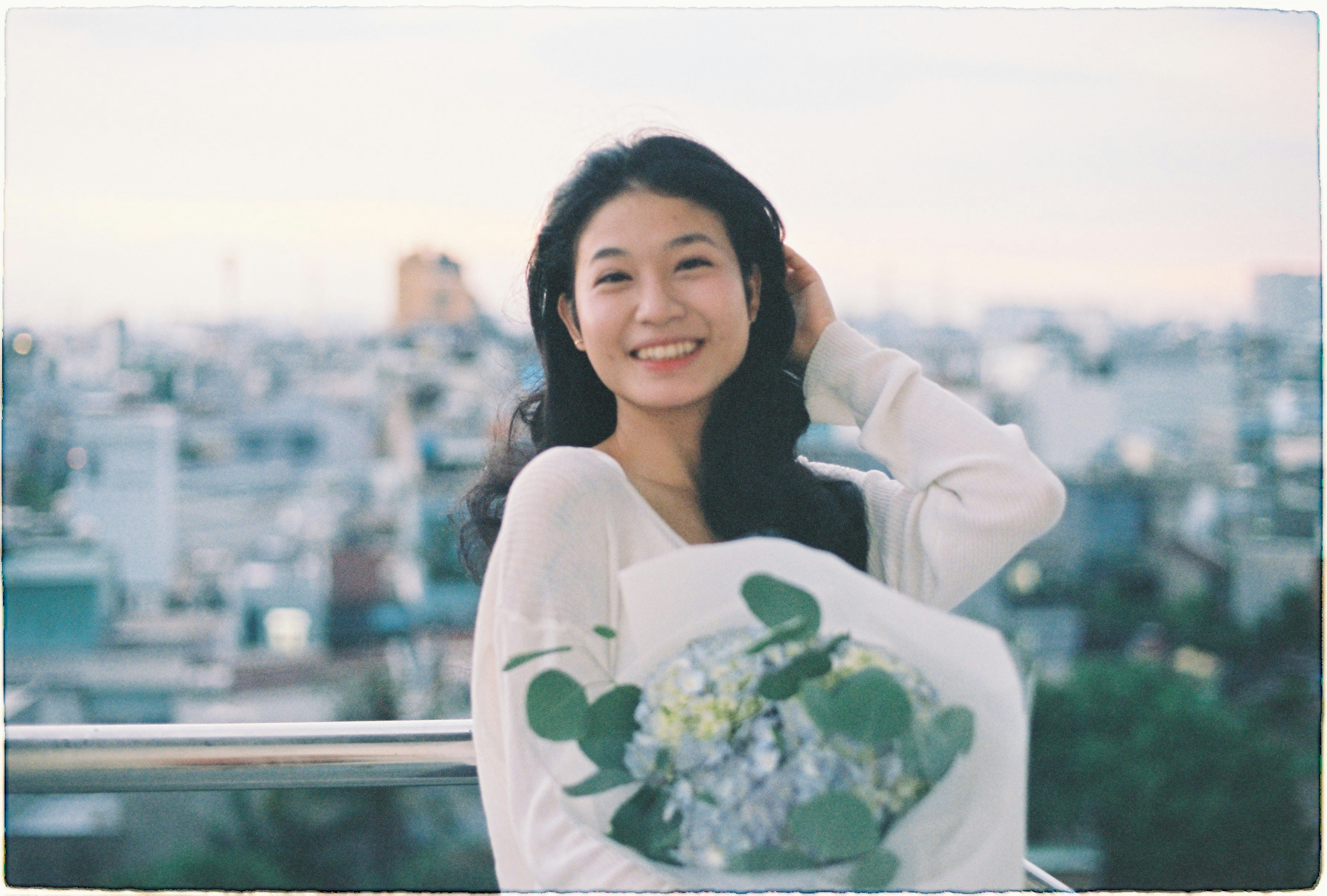 Rooftop Portrait: A Warm Smile Framed by Urban Light and Bouquet