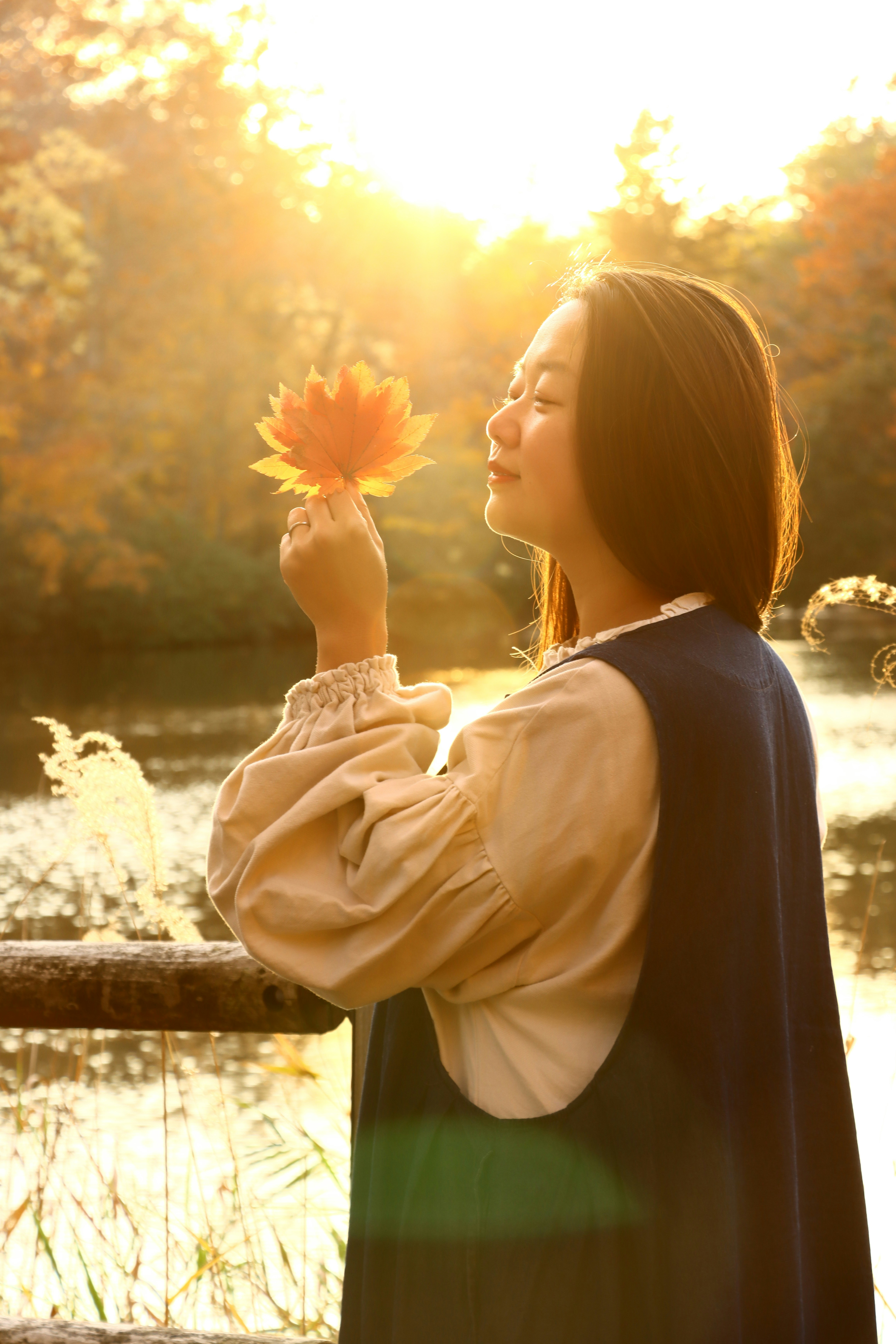 Golden Hour Reverie: Holding a Maple Leaf by the Lakeside