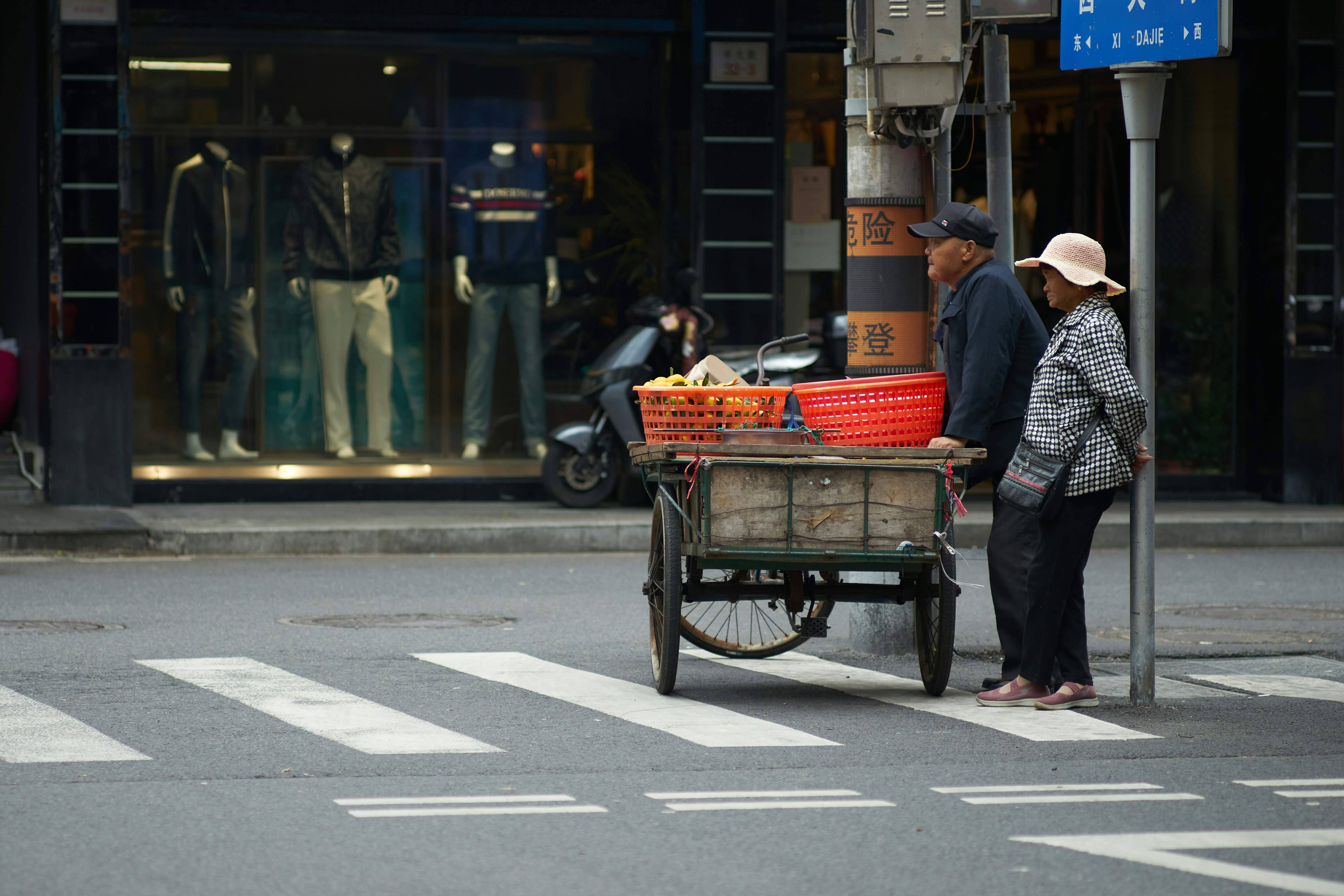 Crosswalk Cart with Orange Baskets: A Quiet Moment of Urban Trade