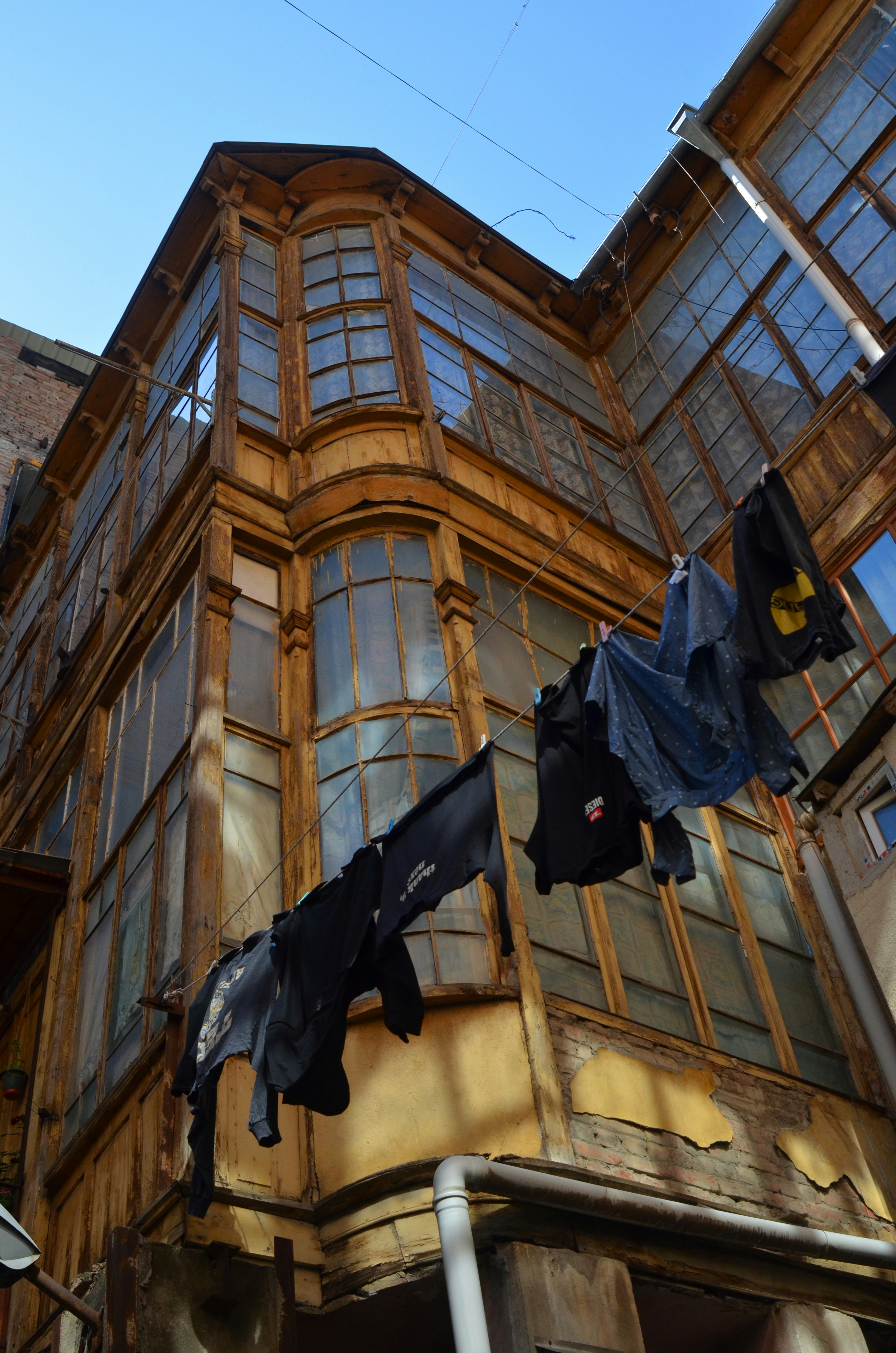 Rust-Toned Bay Windows and Laundry Across a Weathered Corner Facade