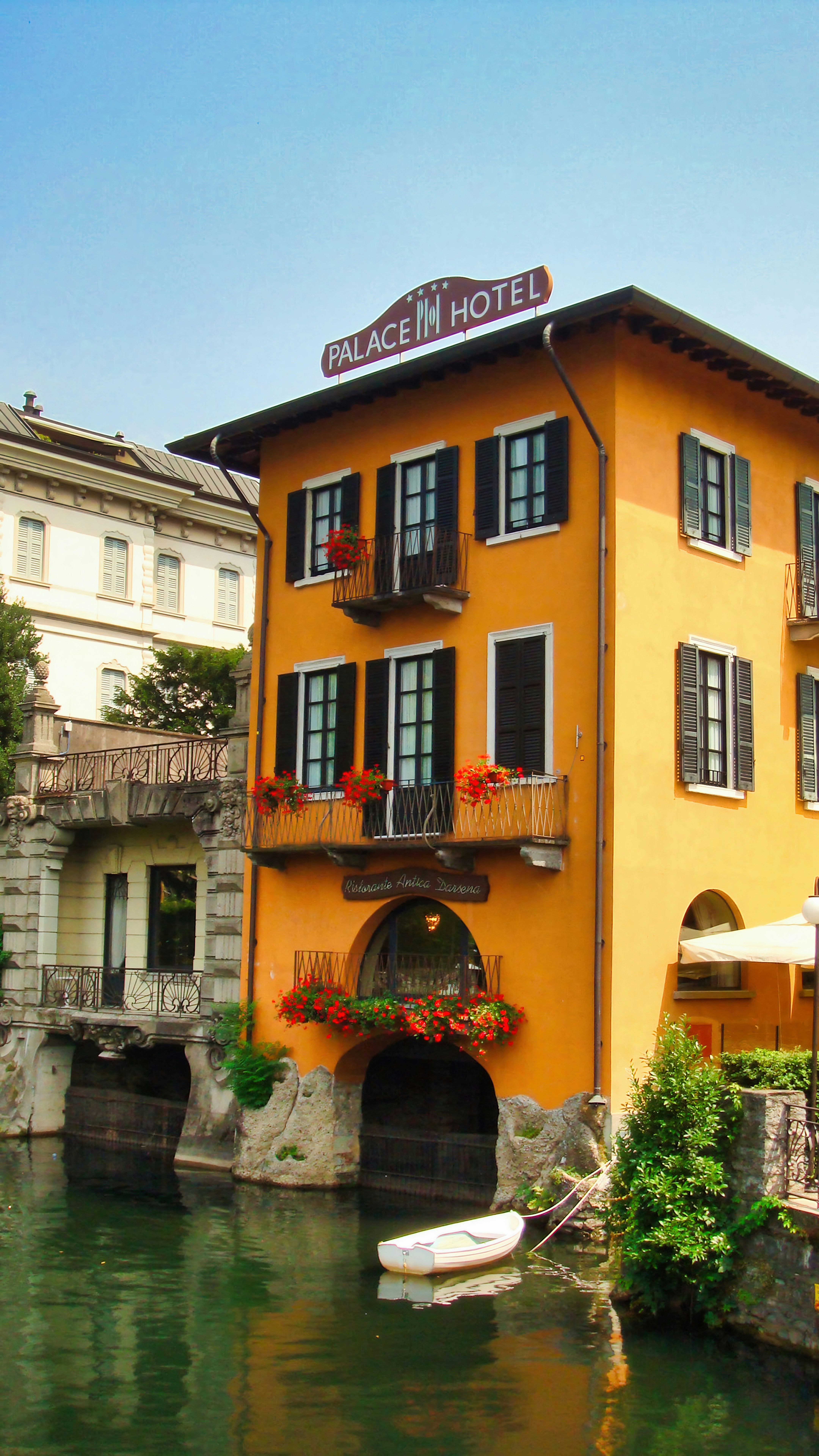 Orange hotel building on a canal with a small boat.