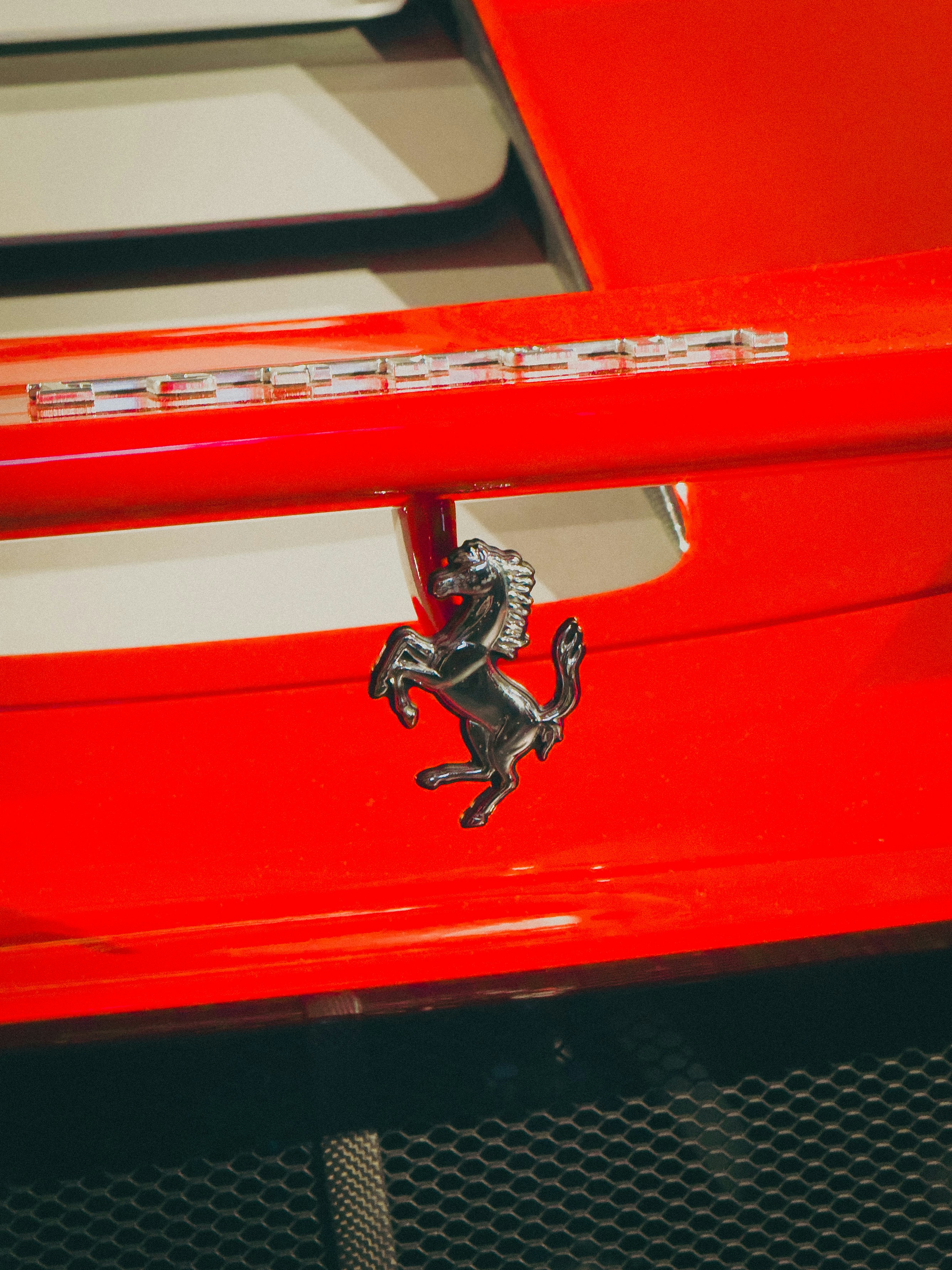 Crimson Grille: The Ferrari Prancing Horse Emerges in Chrome Against Glossy Red