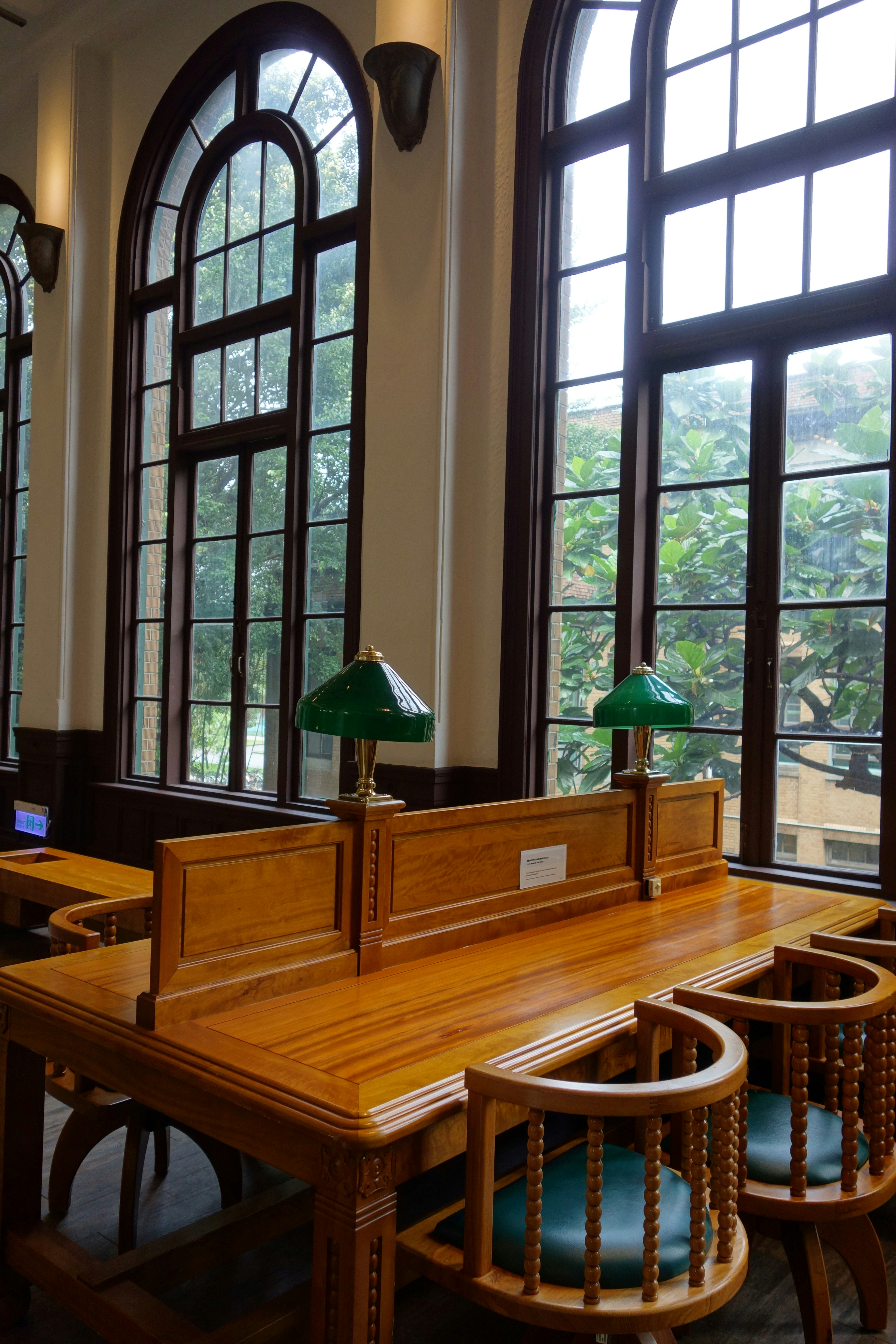 Cedar Quietude: Twin green banker lamps guard a long library desk beneath arched windows
