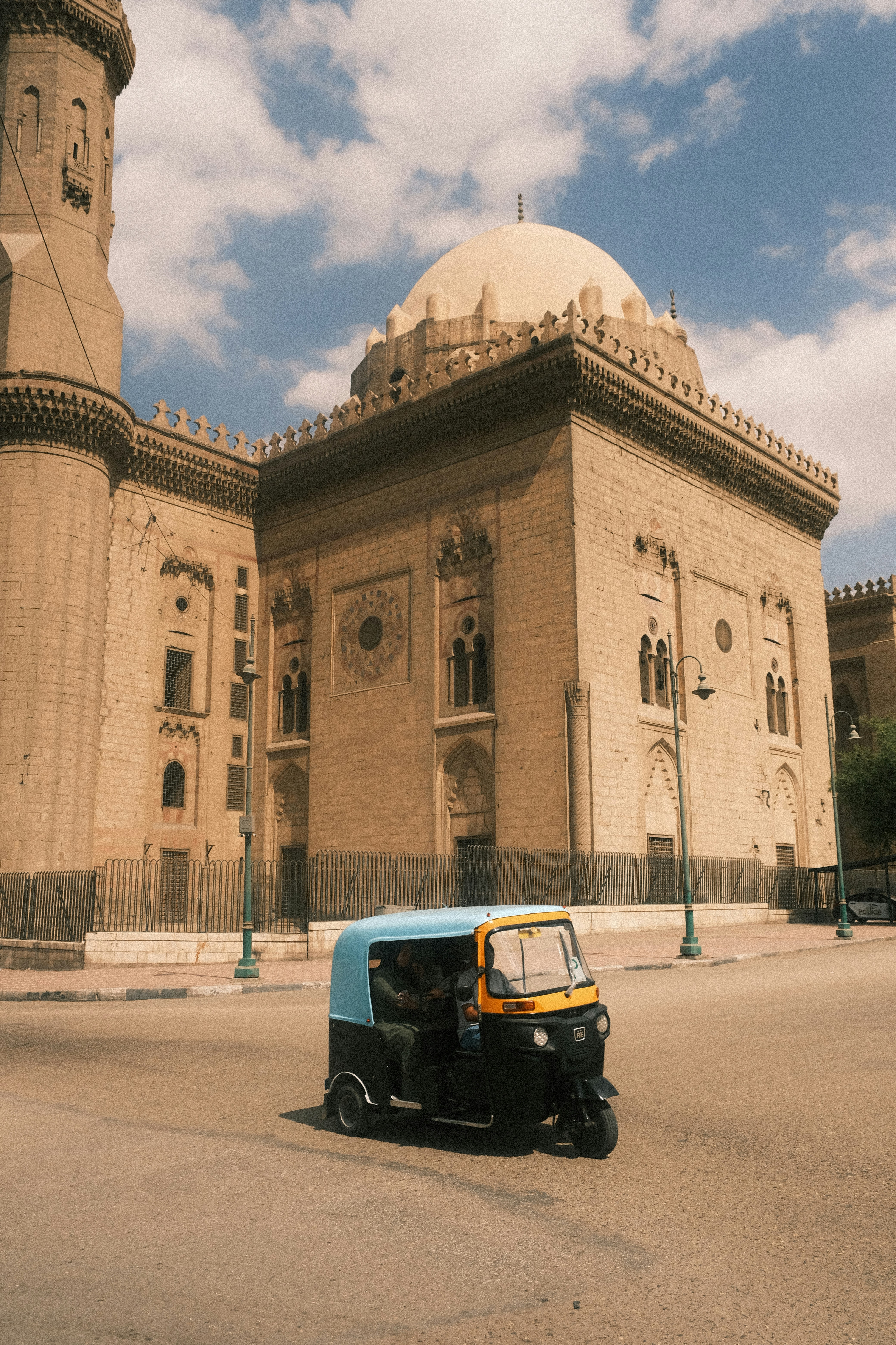 Blue-Topped Tuk-Tuk Defines a Sepia Street Scene Before a Dome-Crowned Fortress
