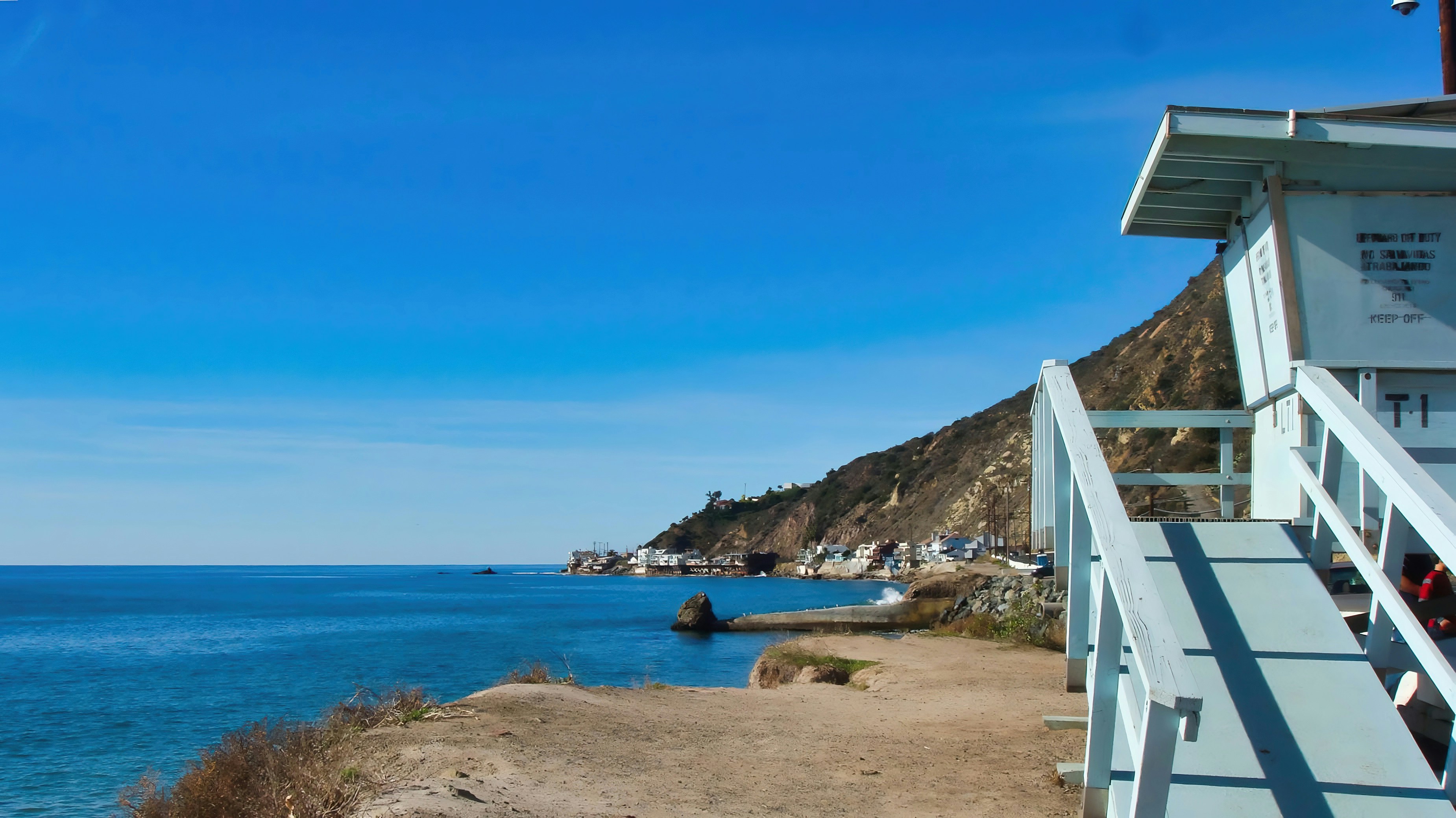 Lifeguard tower overlooking a calm blue ocean and beach.
