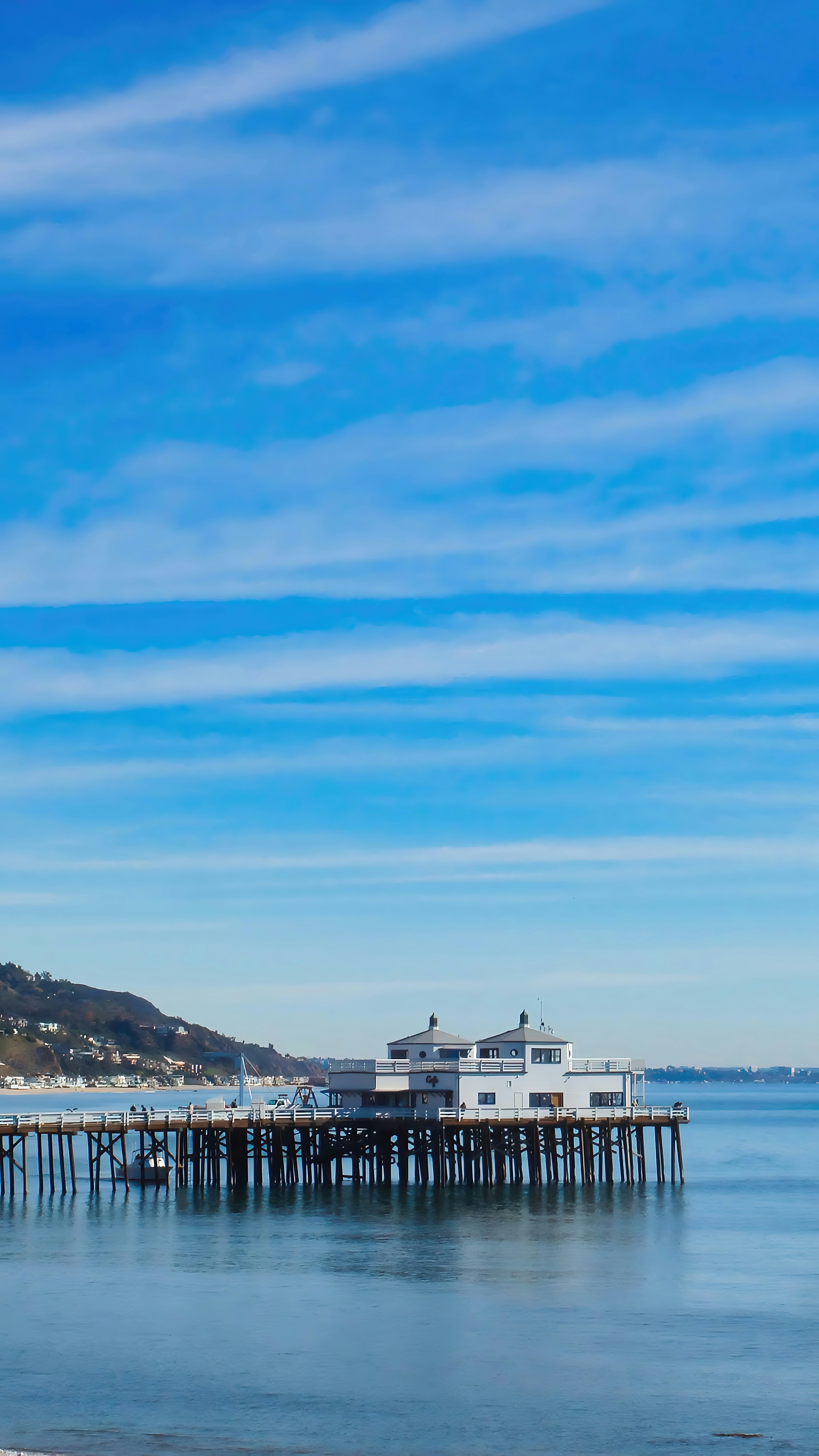 A white building on a pier over the ocean.