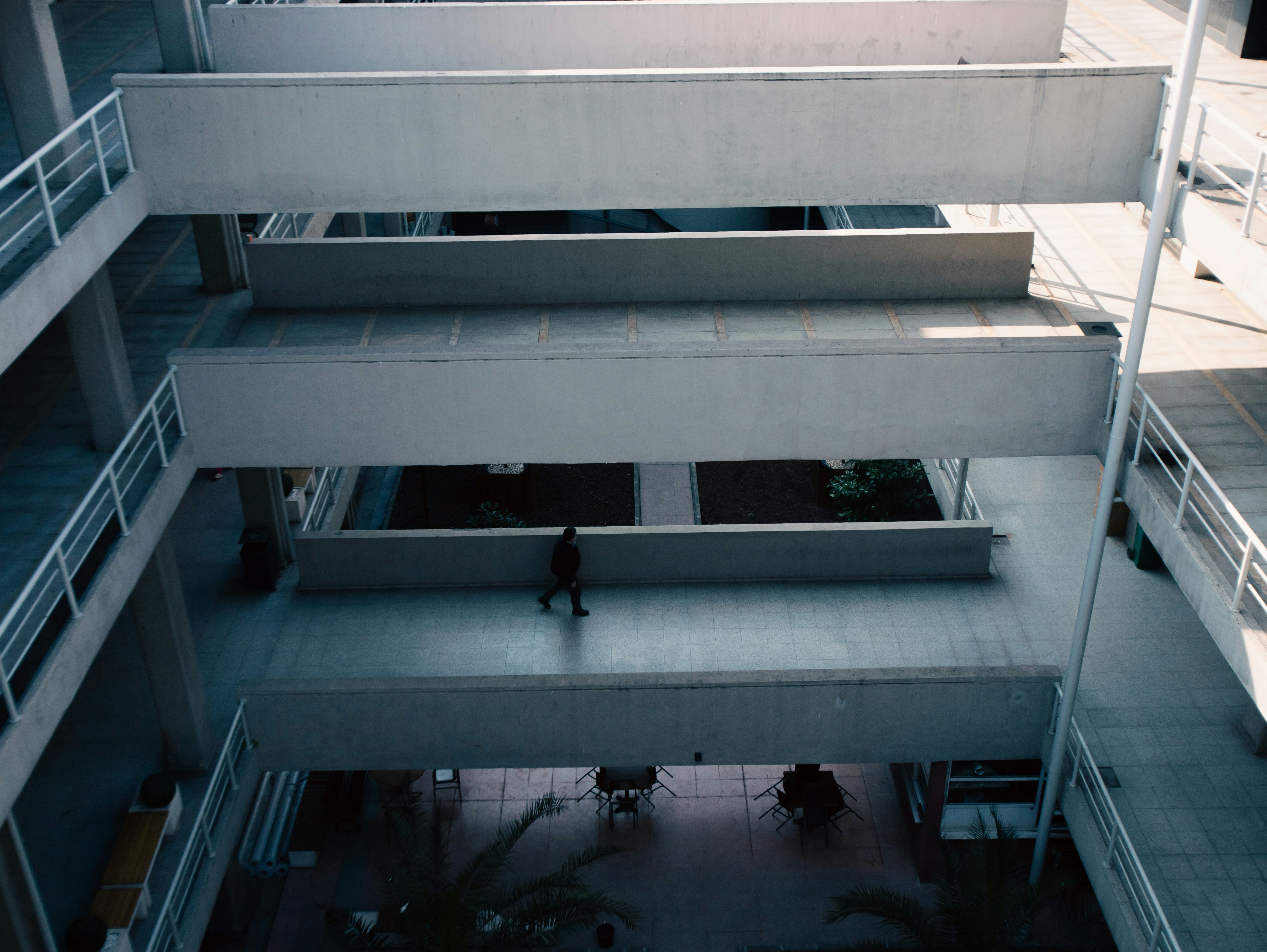 Mid-Level Silence: A Solitary Figure Crosses the Brutalist Atrium