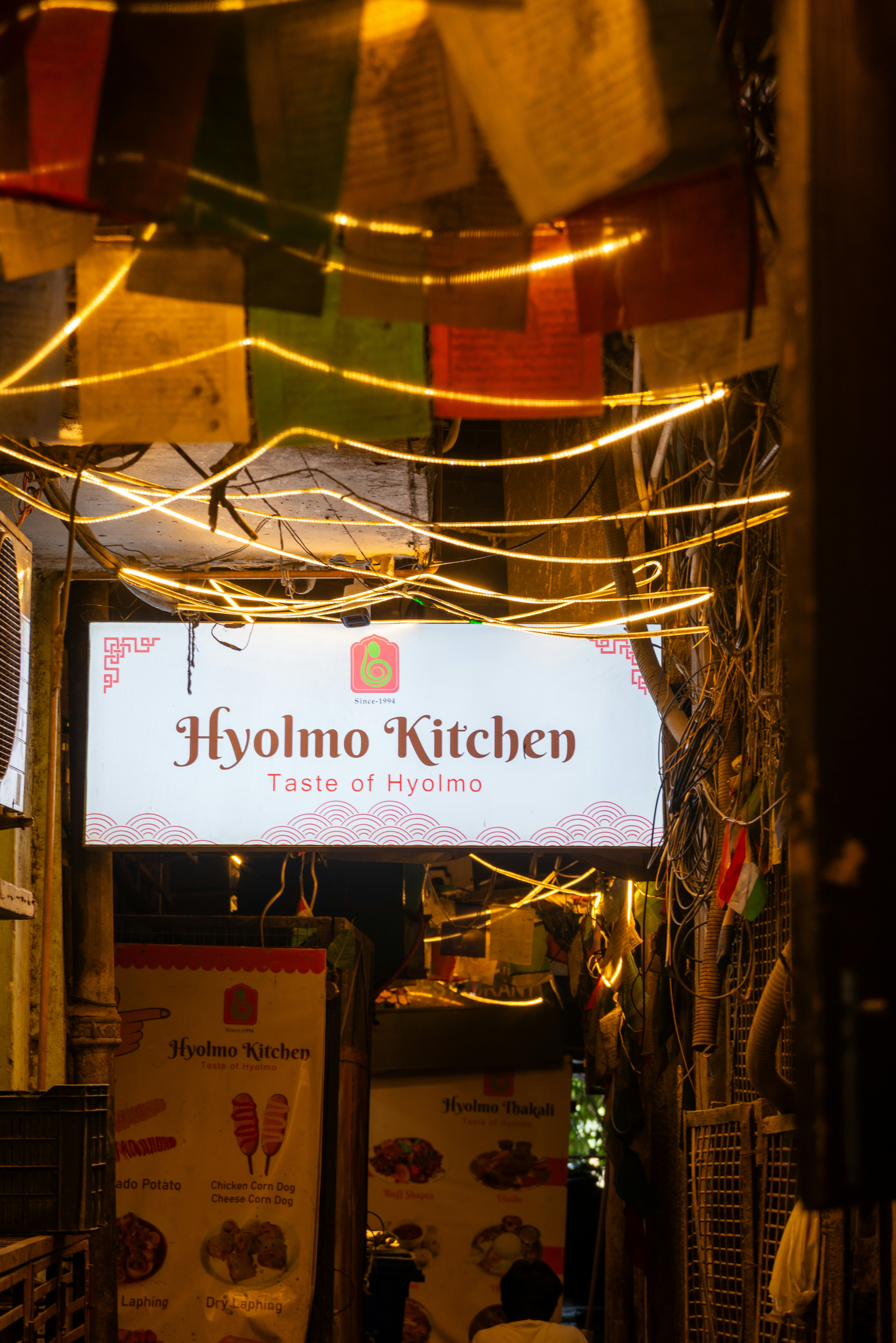 Lantern-lit Alleyway Framing the Hyolmo Kitchen Sign at Dusk
