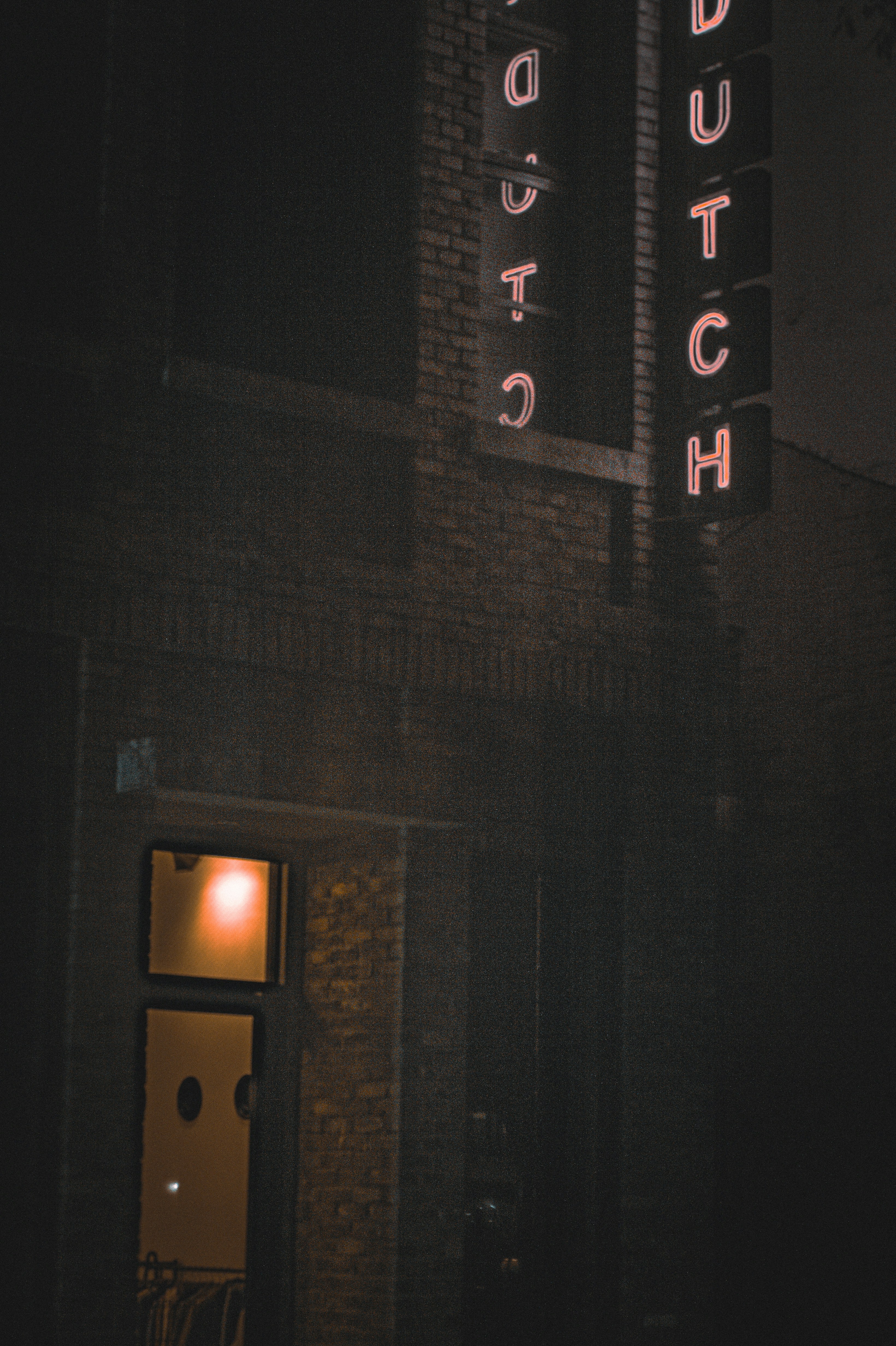 Neon Dutch Sign Illuminates a Brick Facade at Night