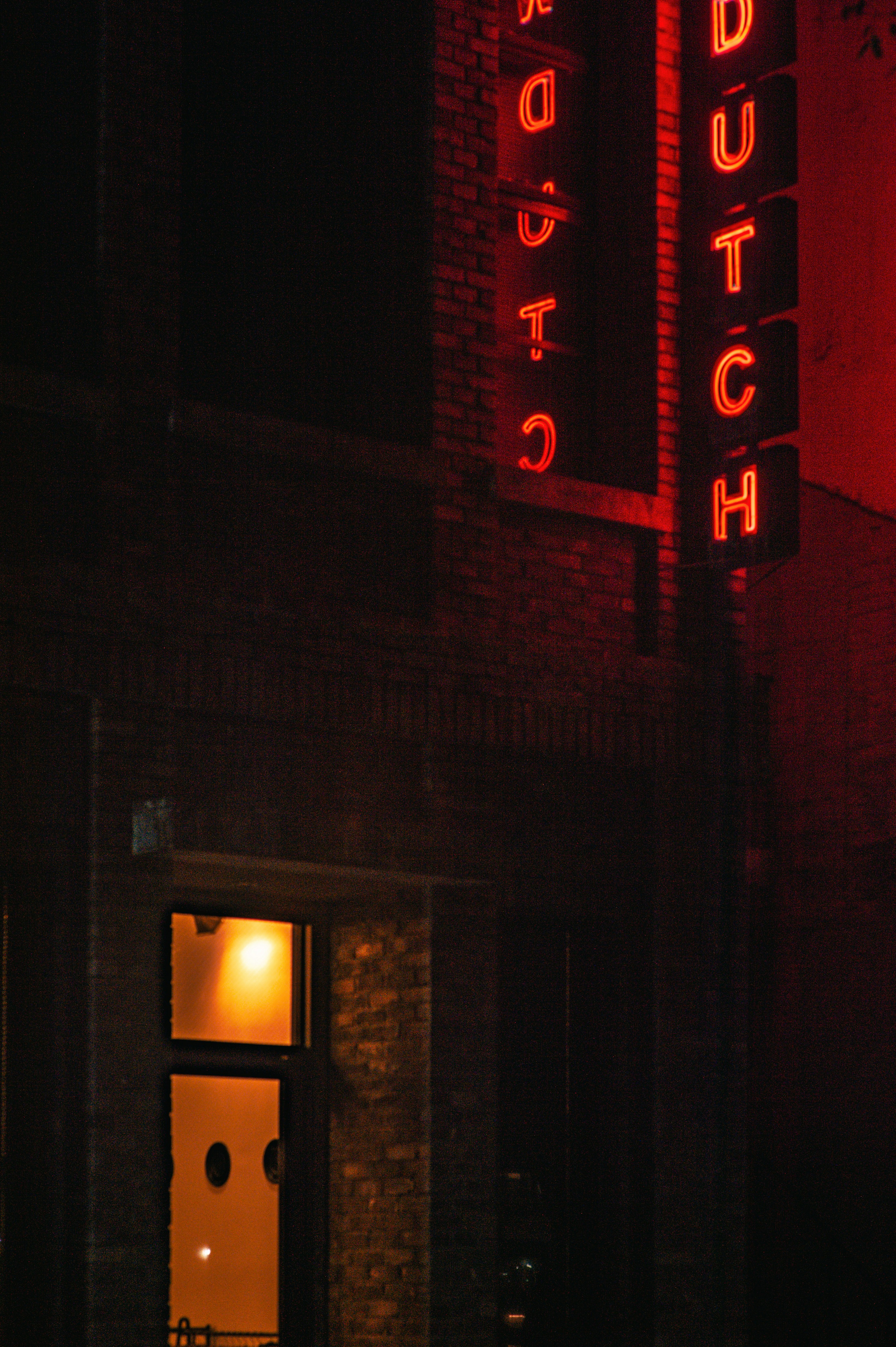 Crimson Neon Over Brick Facade: Night Entrance