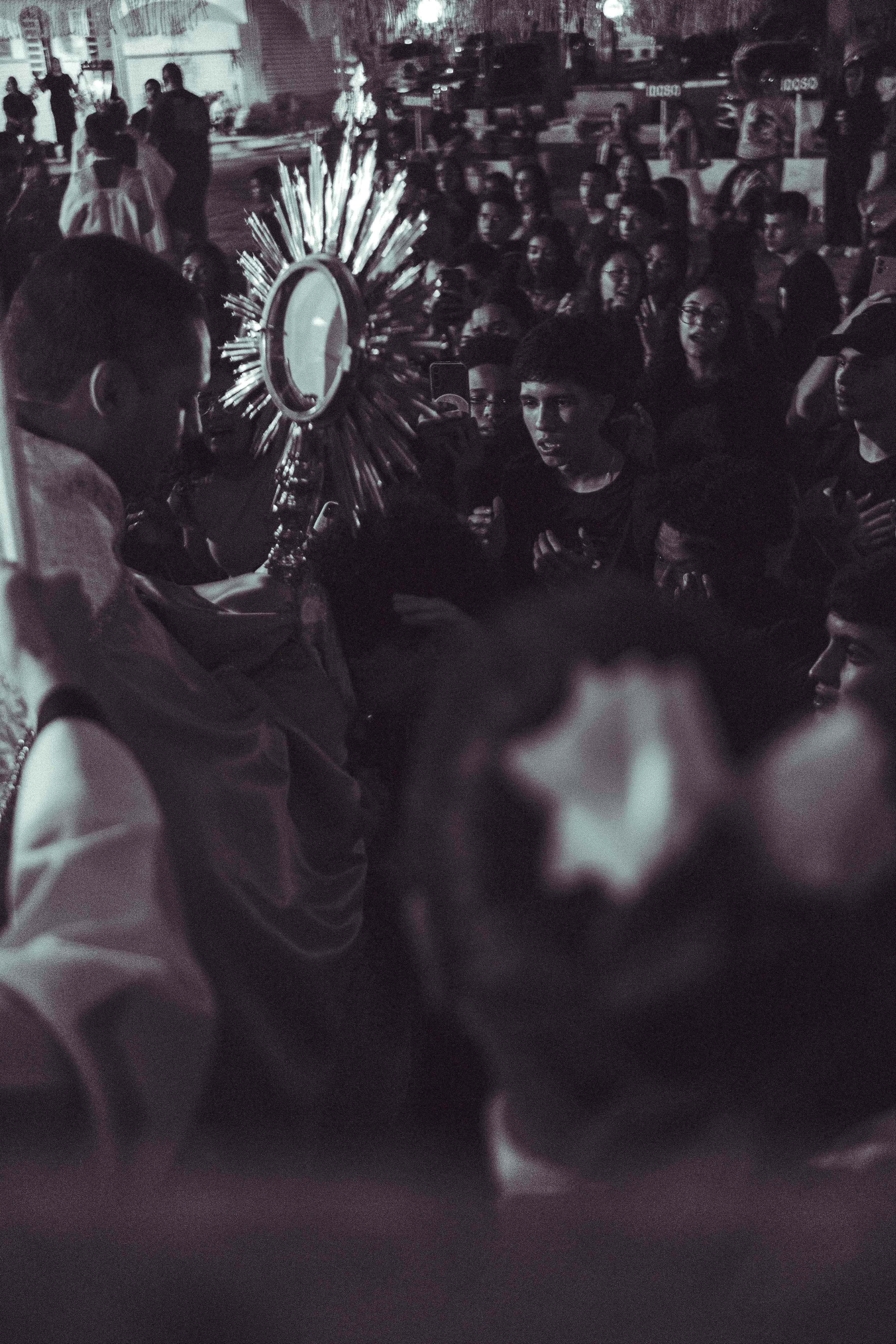 Sunburst Monstrance Amid a Night Vigil: A Candid Crowd with Smartphones
