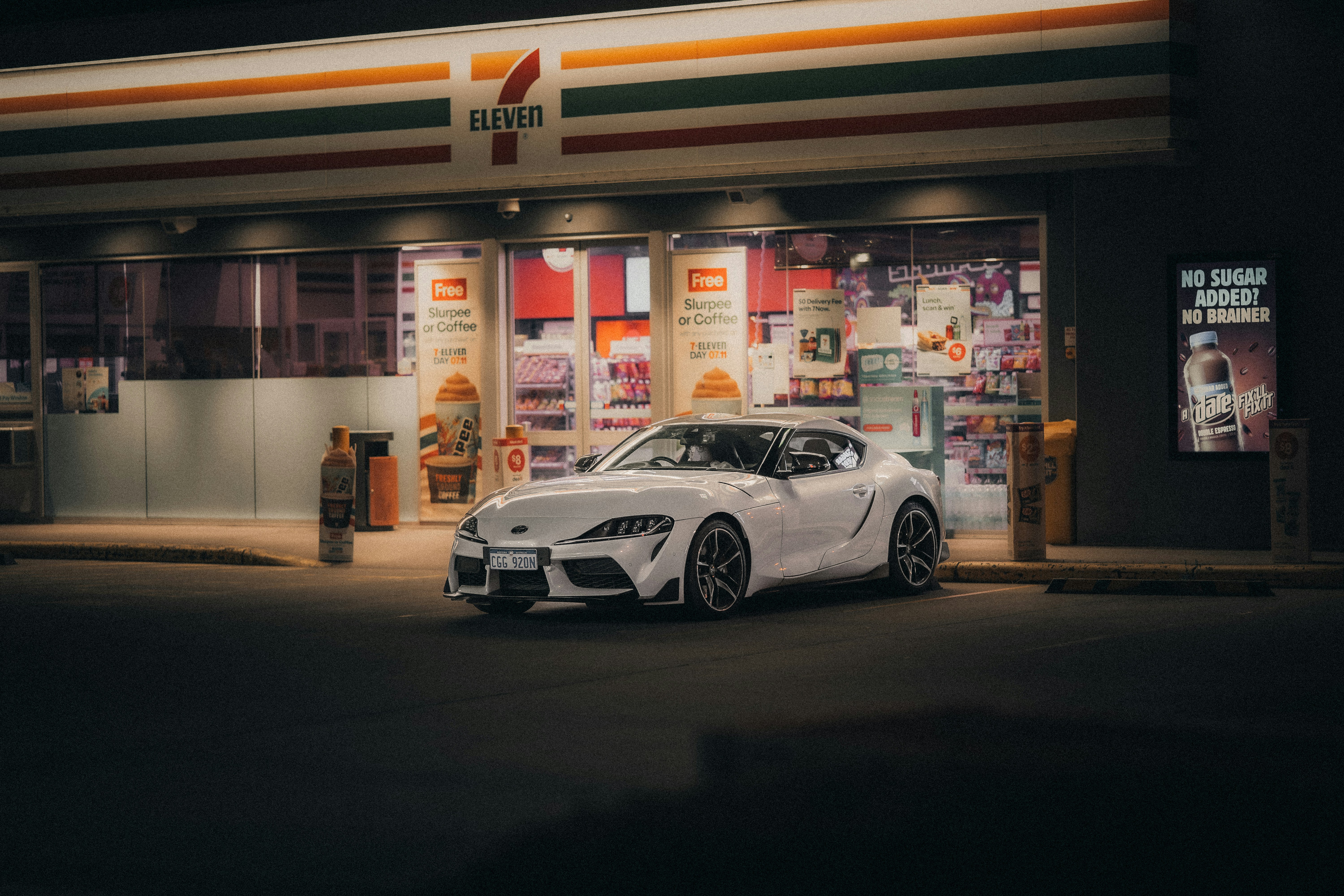 Midnight Pit Stop: White Sports Car Beneath Neon Seven-Eleven Sign