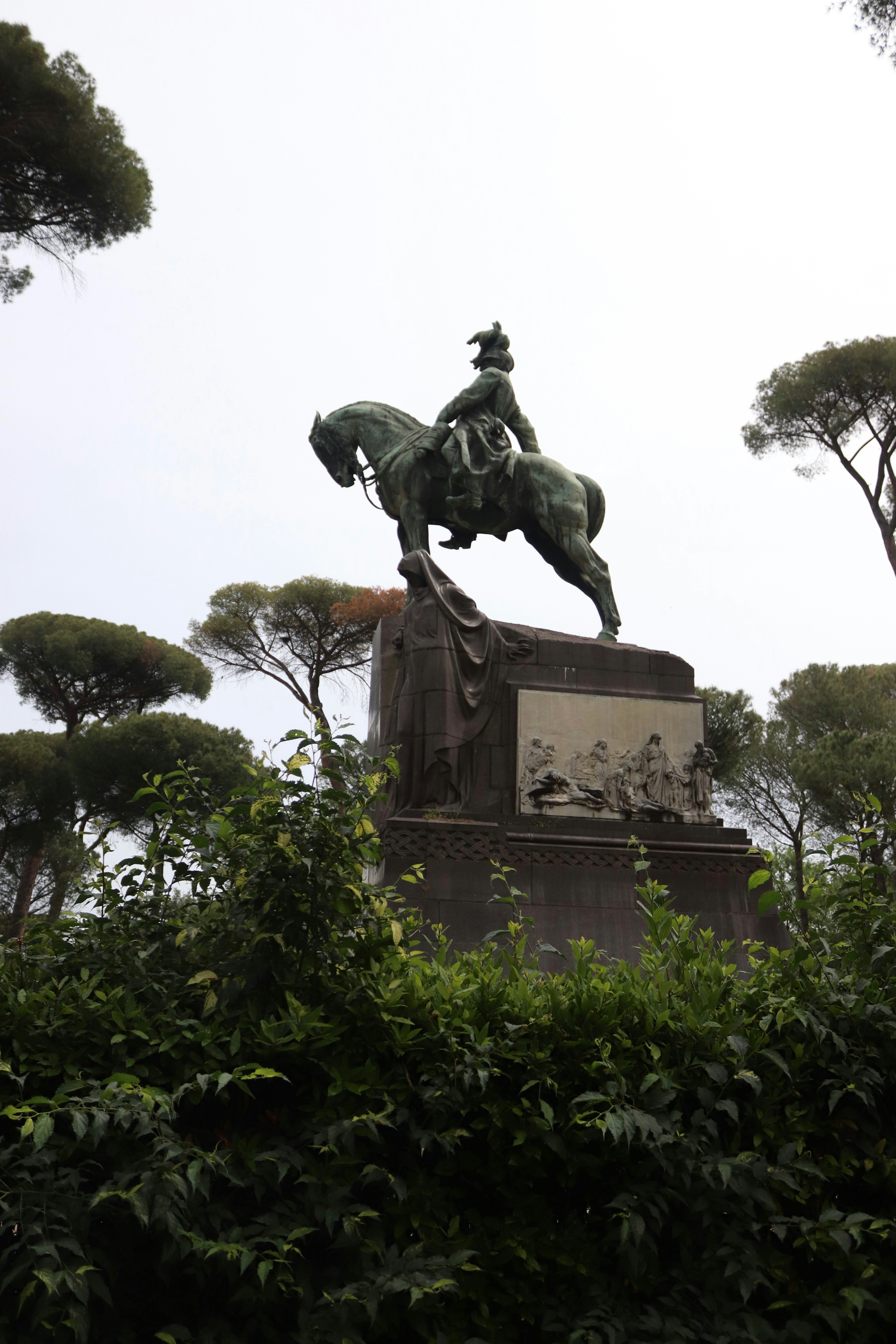 Equestrian Bronze Amid Pines: A Park Monument Framed by Foliage