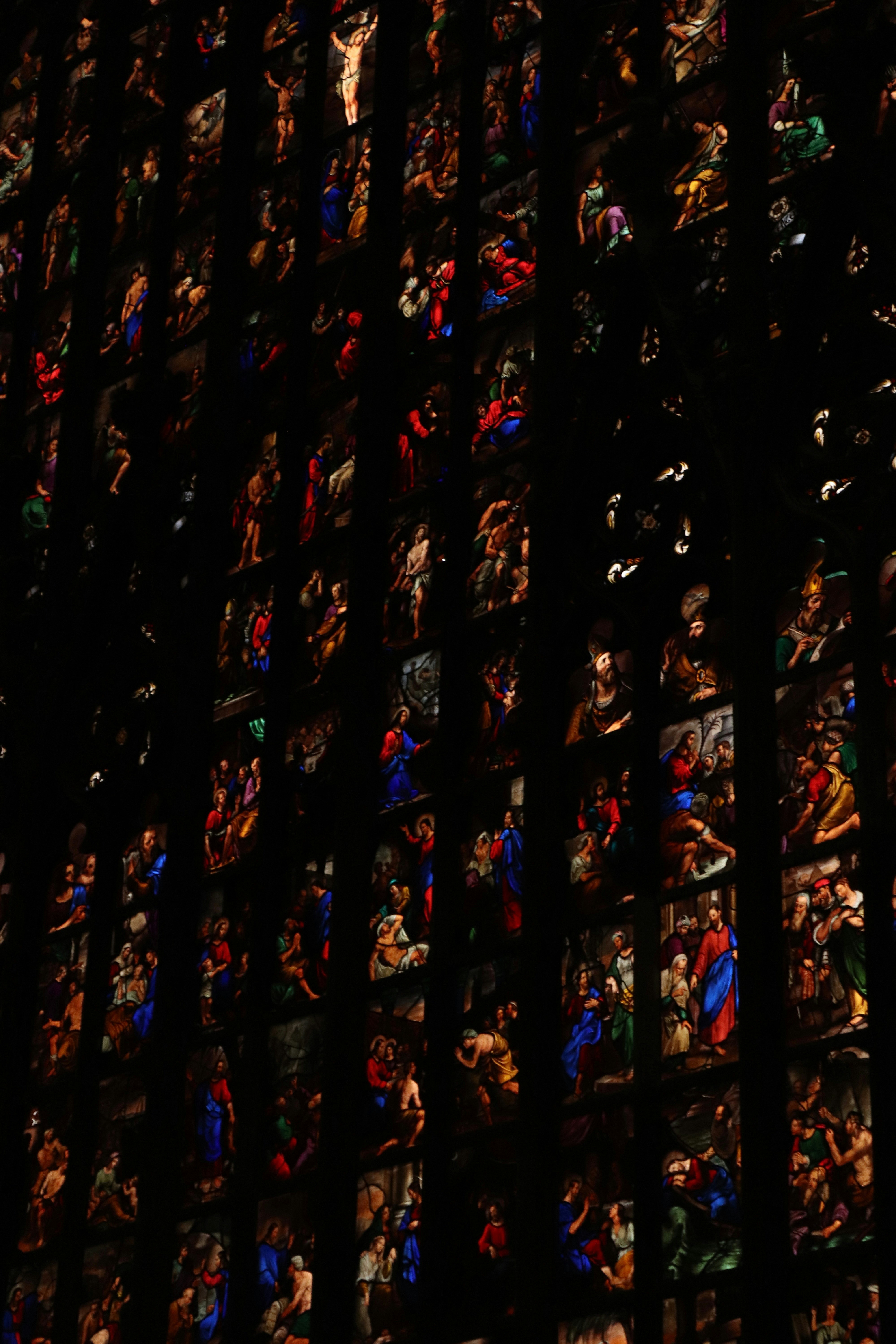 Stained-Glass Grid: A Cathedral Mosaic of Figures Illuminated in Shadow