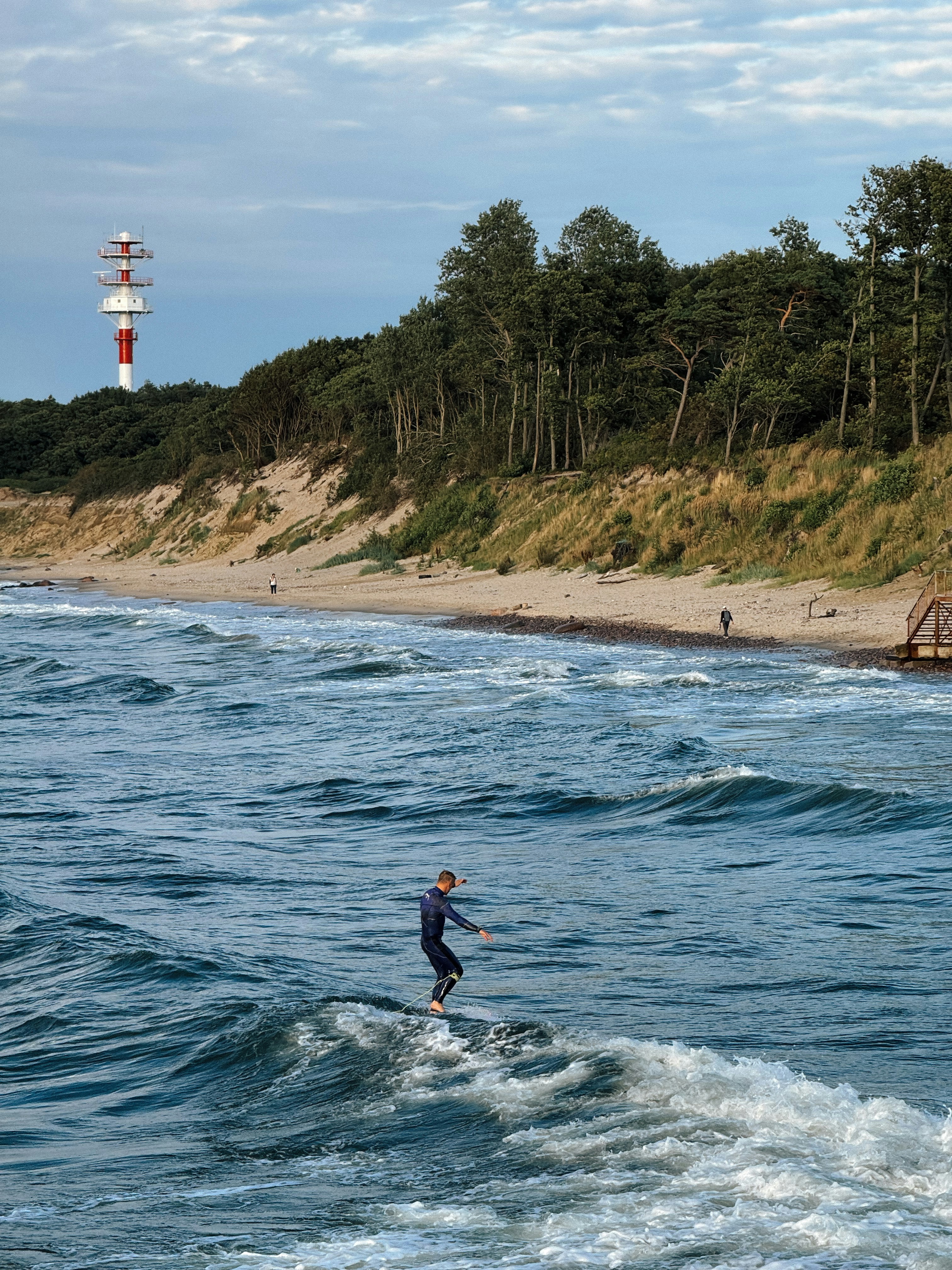 Surfer on a Coastal Wave Under a Quiet Dune Forest
