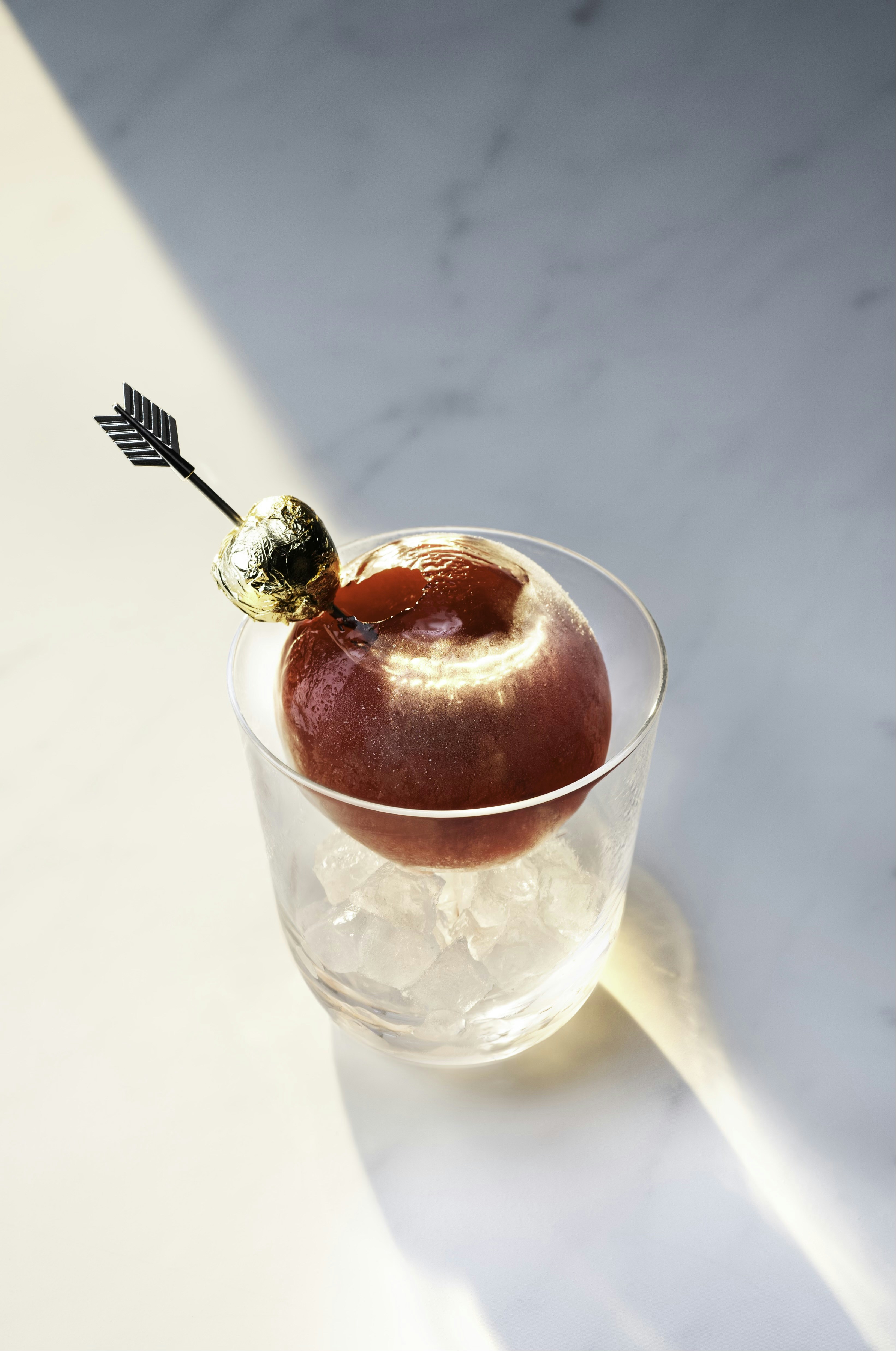 Red apple with arrow skewer in glass
