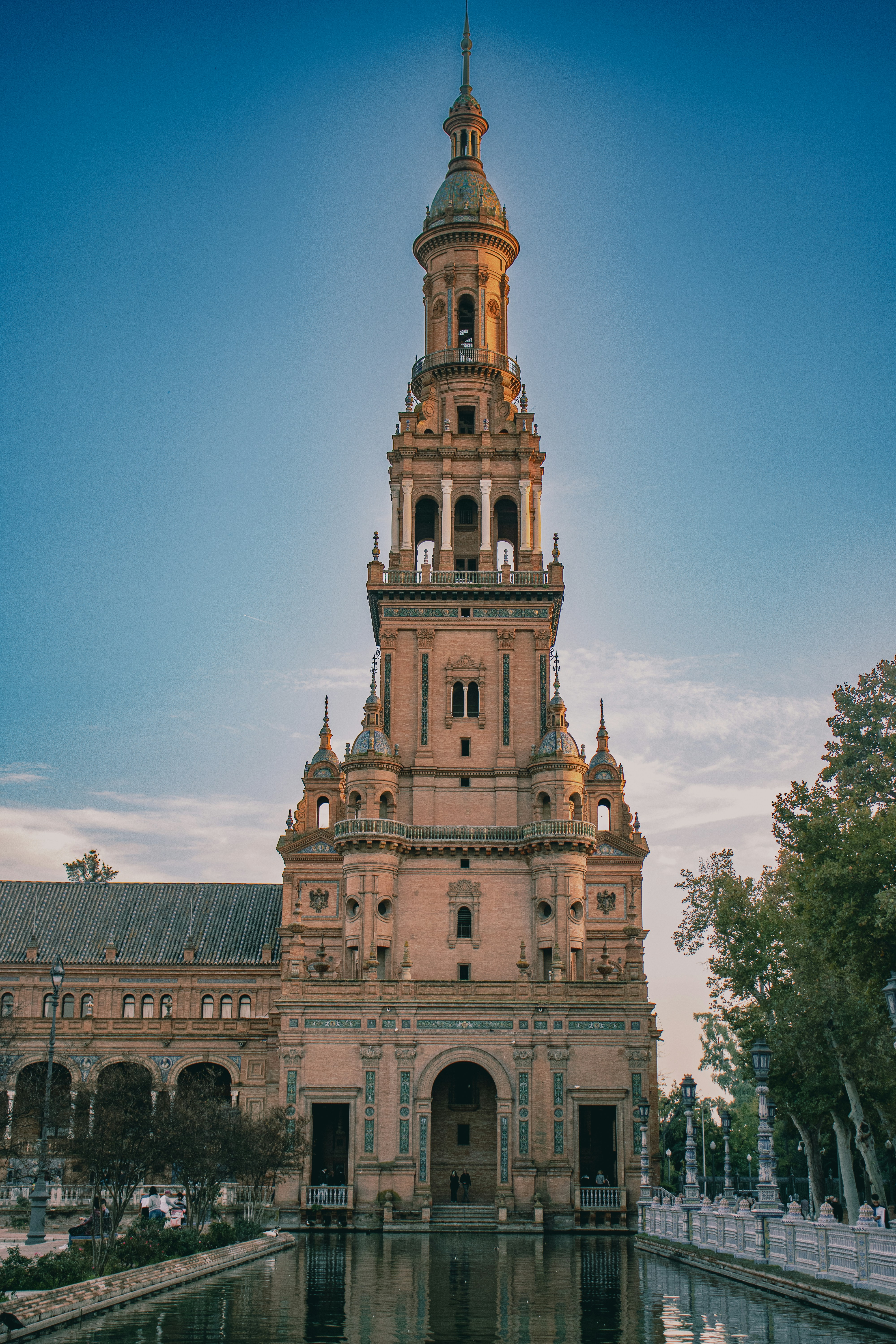 The South Tower (Torre Sur) of Plaza de España in Seville ornate Regionalist architecture rising above the canal and tiled bridges.