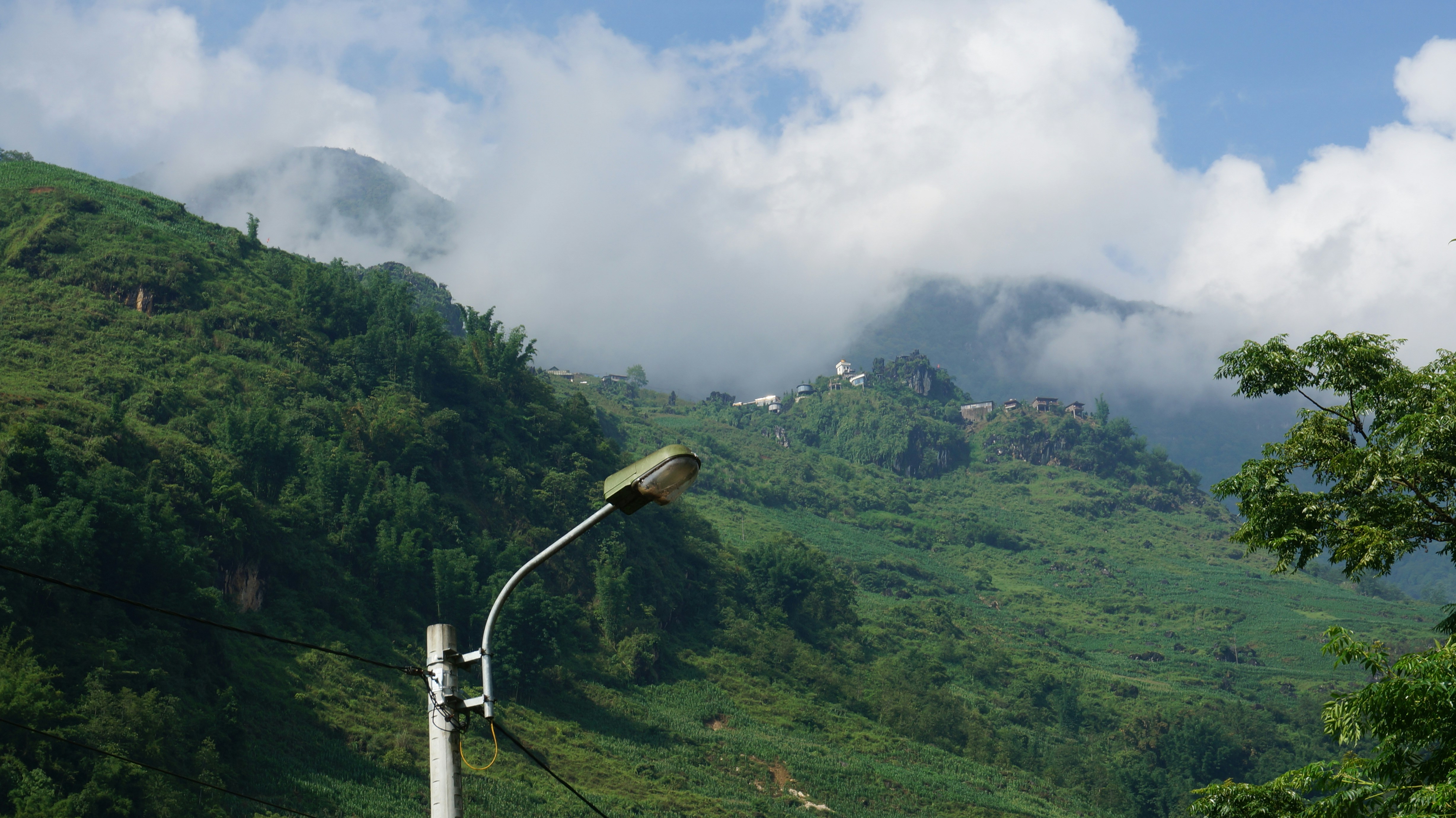 Lone Street Lamp Over Verdant Valley as Clouds Drift Above