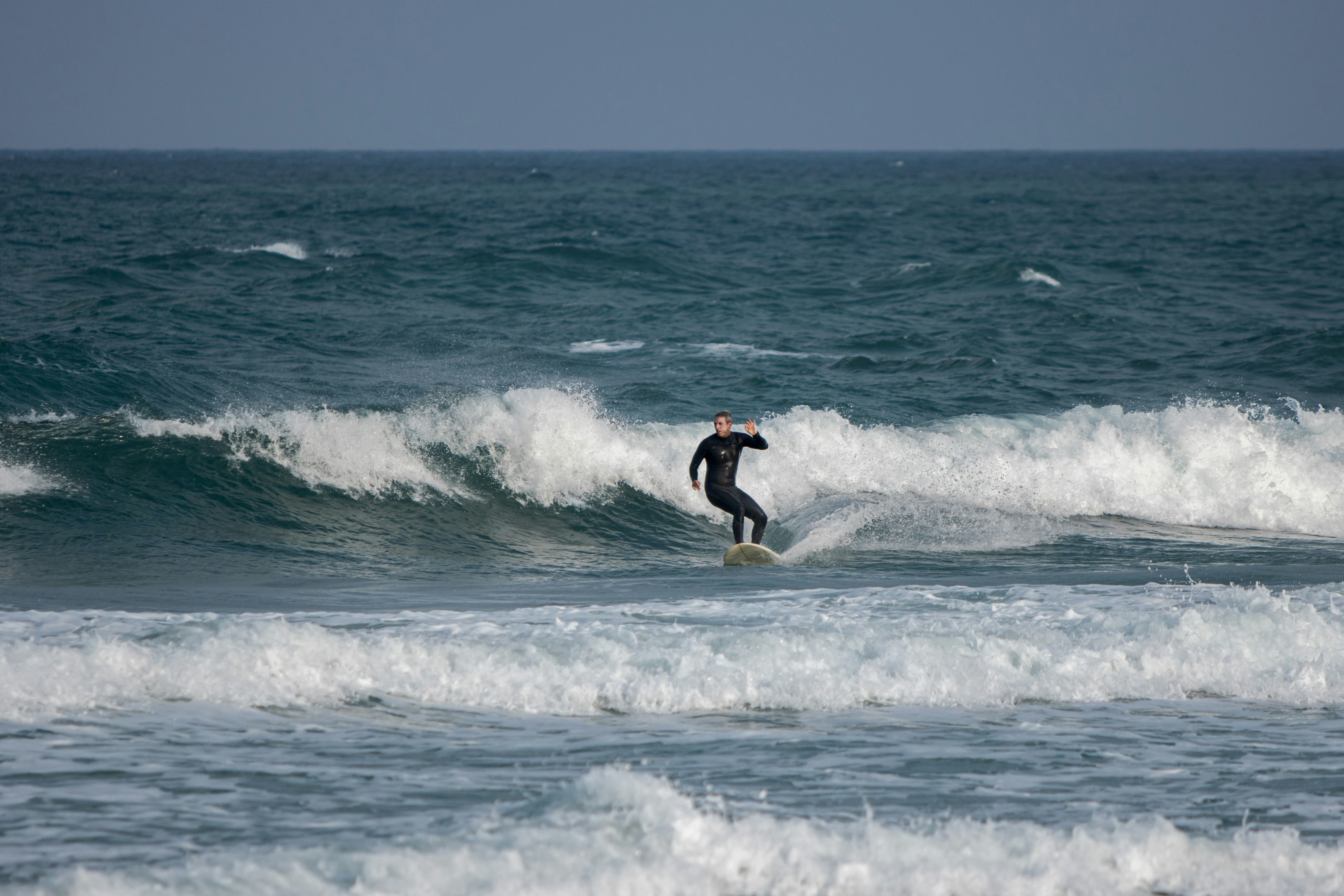 Carving the Crest: A lone surfer traces balance along a foam-laced breaker