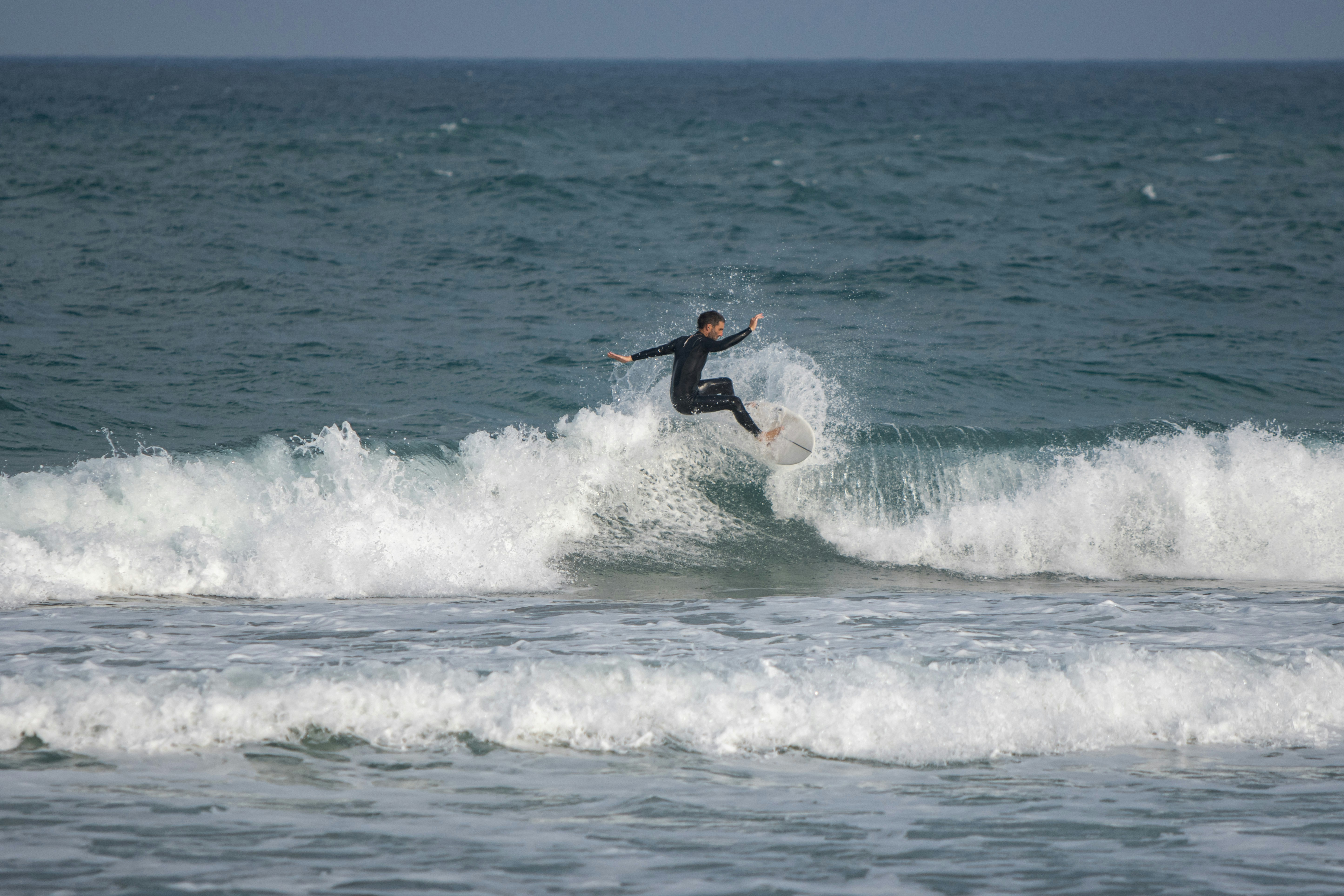 Cresting Momentum: Surfer Slices a Blue Wall