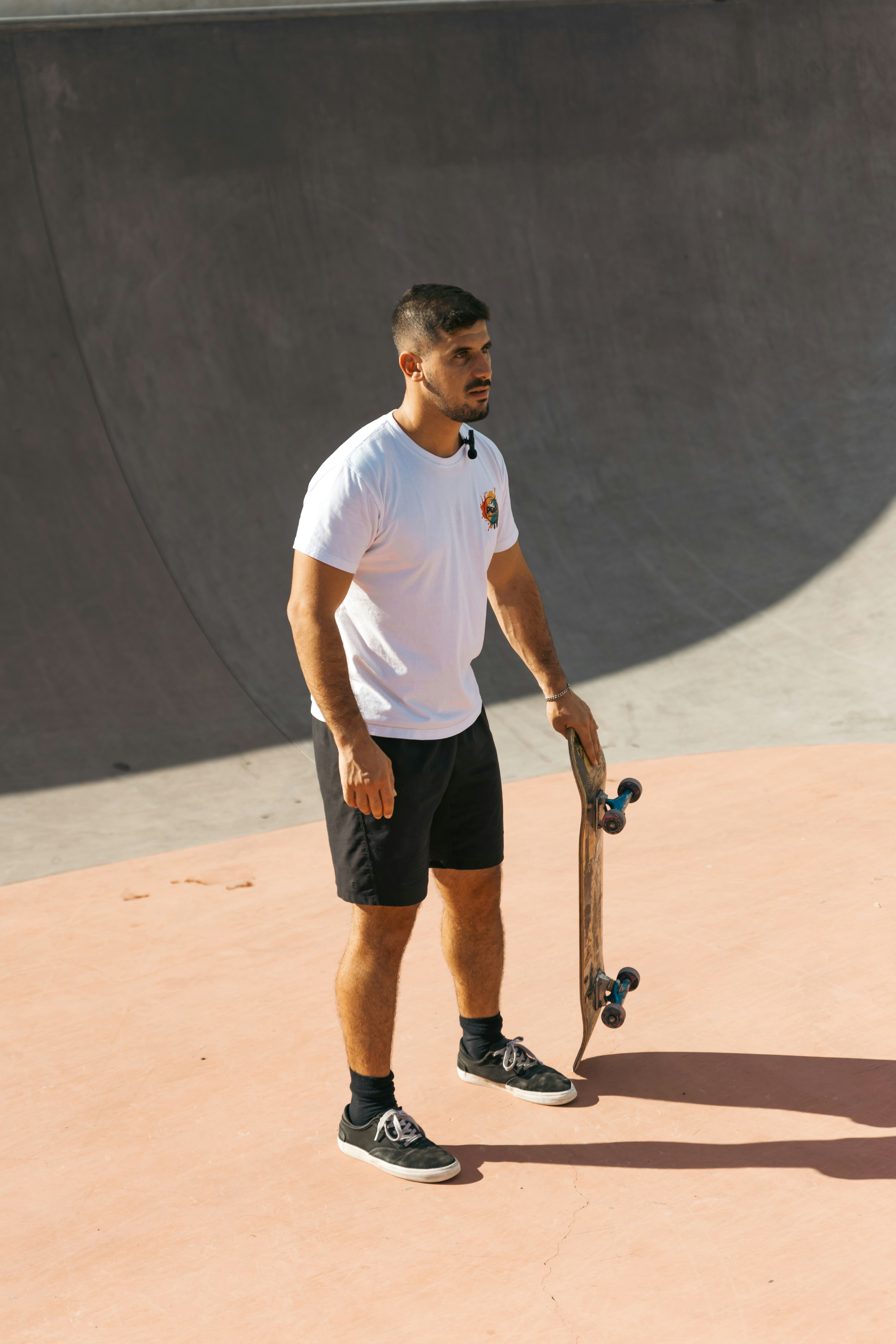 Pause at the Curve: A Skater Stands Ready in a Sunlit Bowl