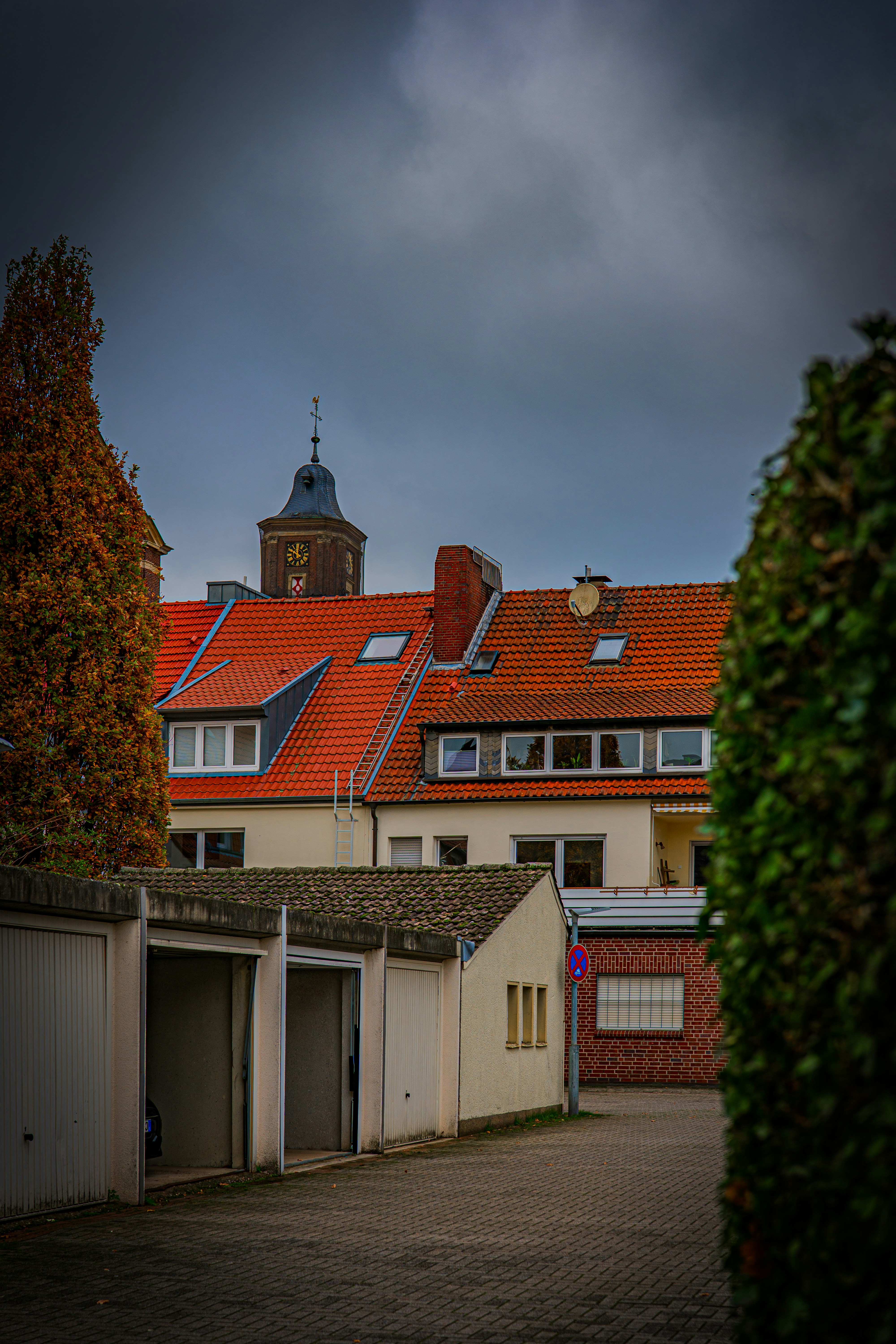 Clock Tower Above a Garage-Fronted Alley and Red Roofscape